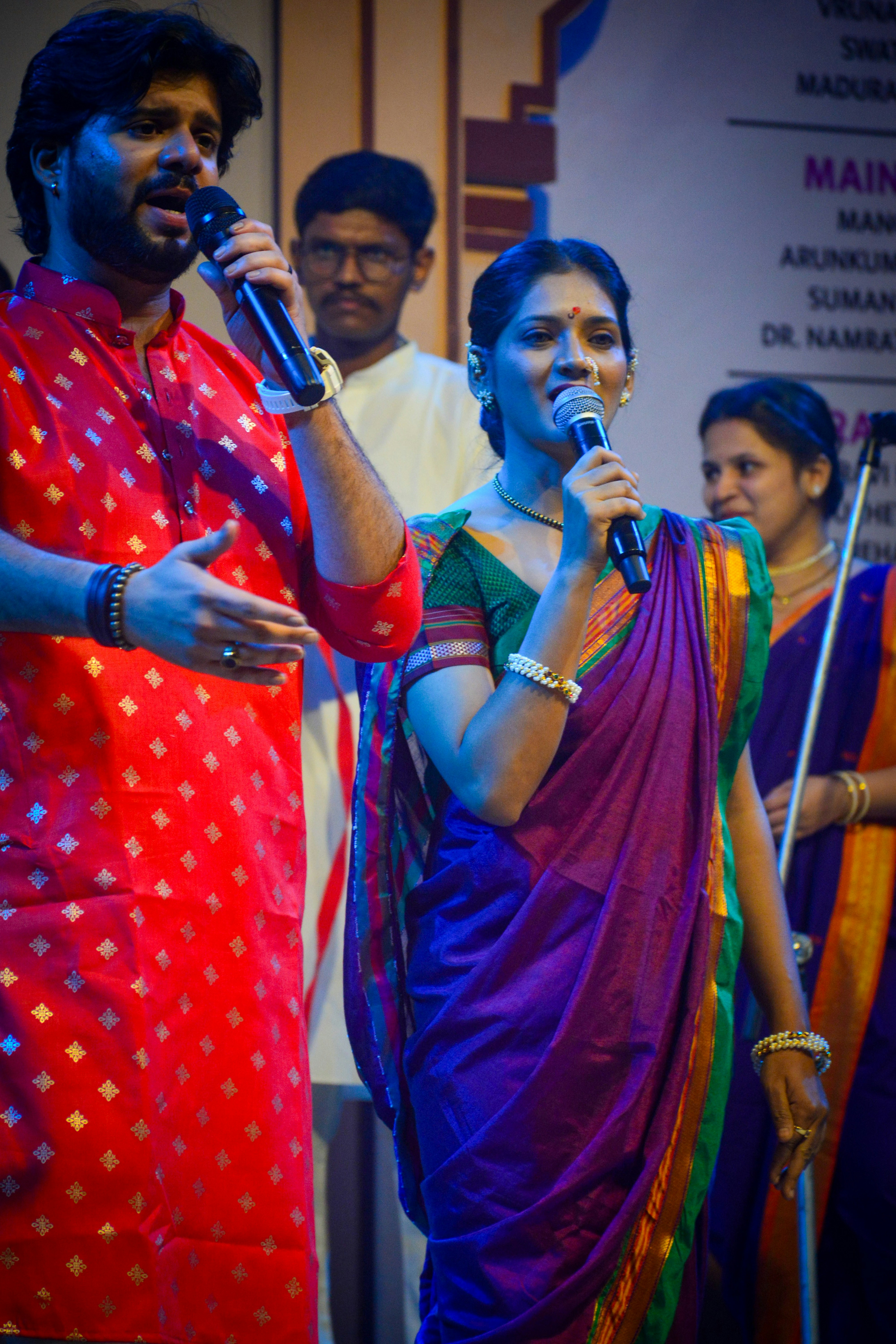 Colorful duet: a duo of singers under stage lights with vibrant sari and red kurta