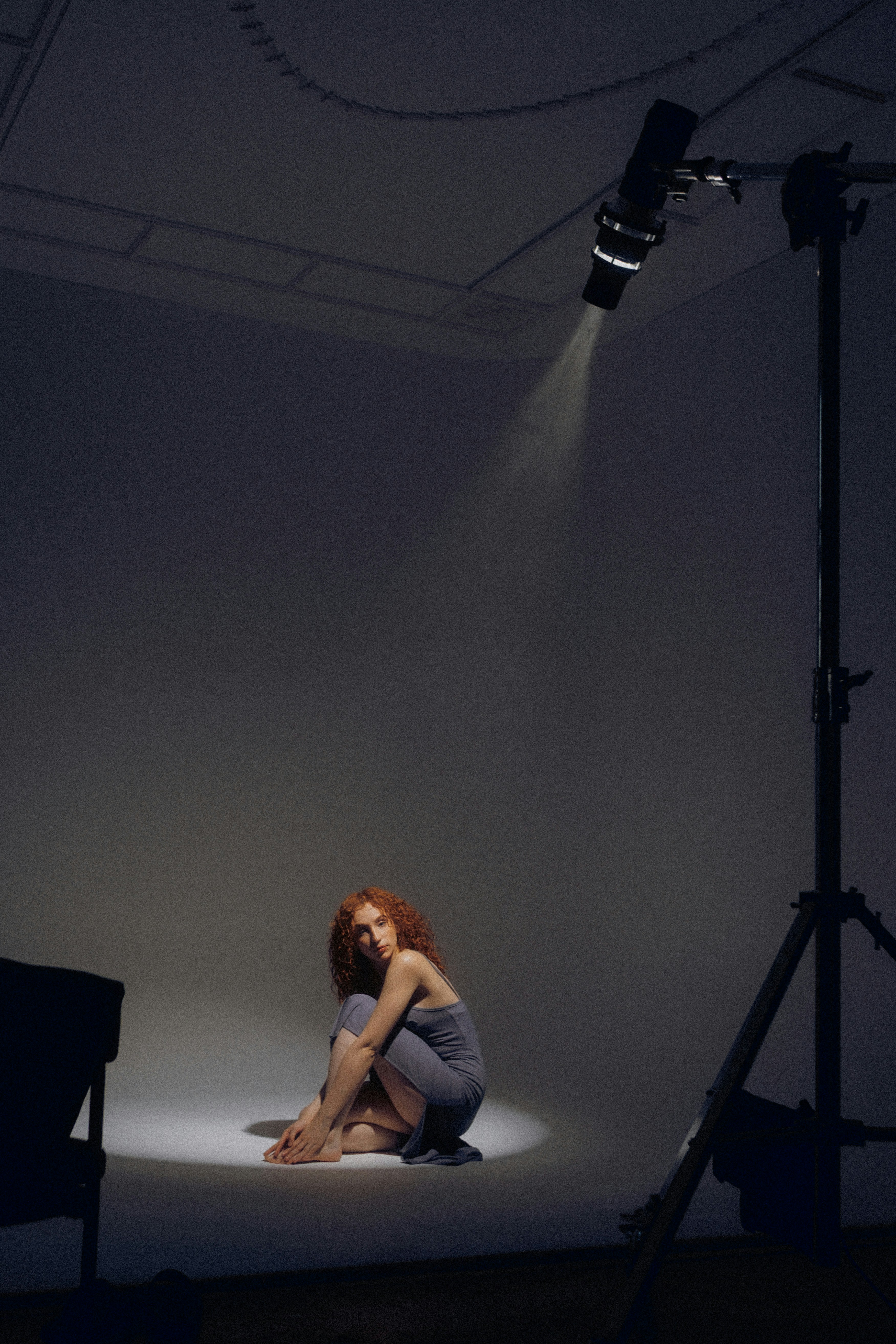 Spotlit Solitude: A Redheaded Model in a Quiet Studio