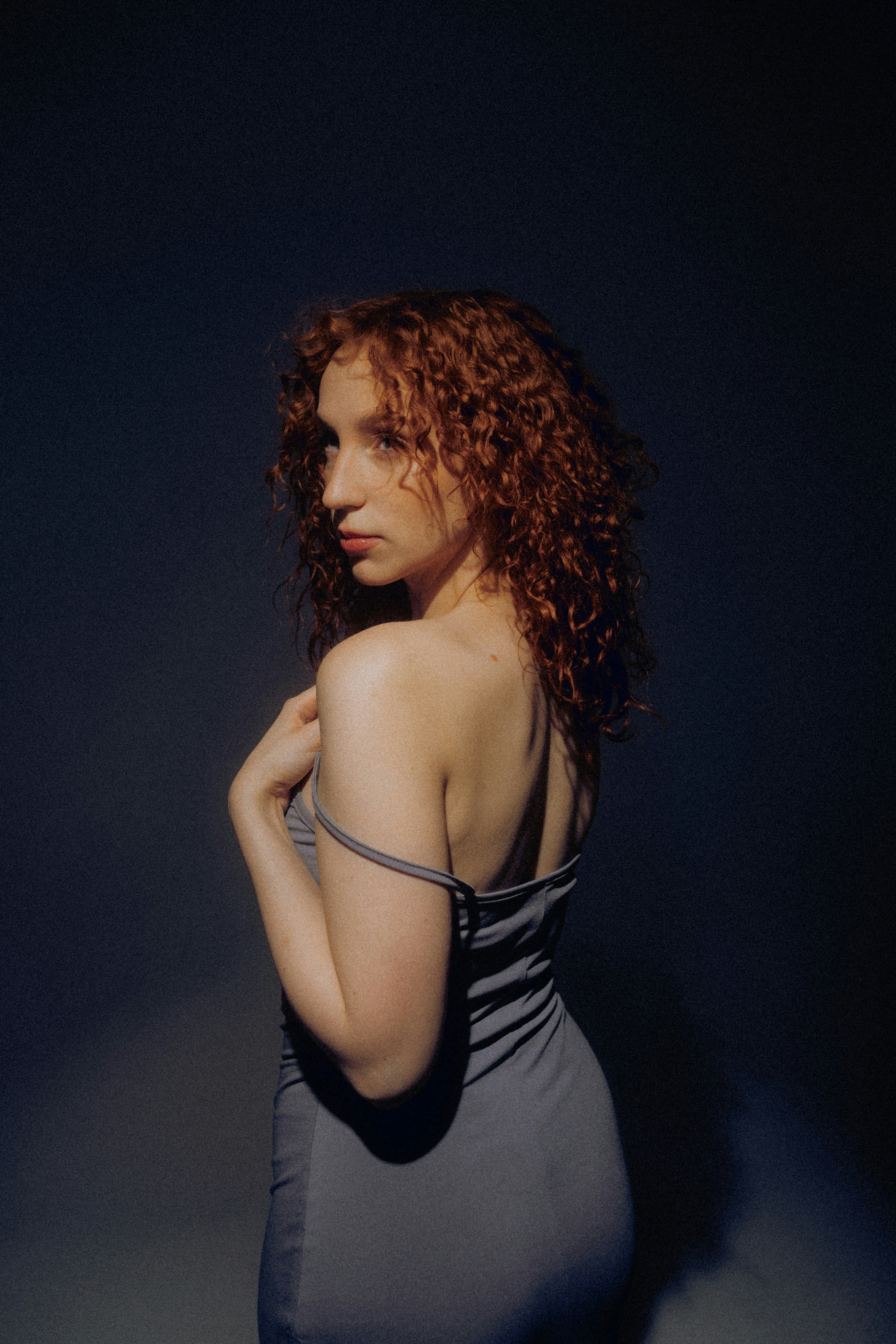 Red-haired silhouette: a poised portrait against velvet darkness