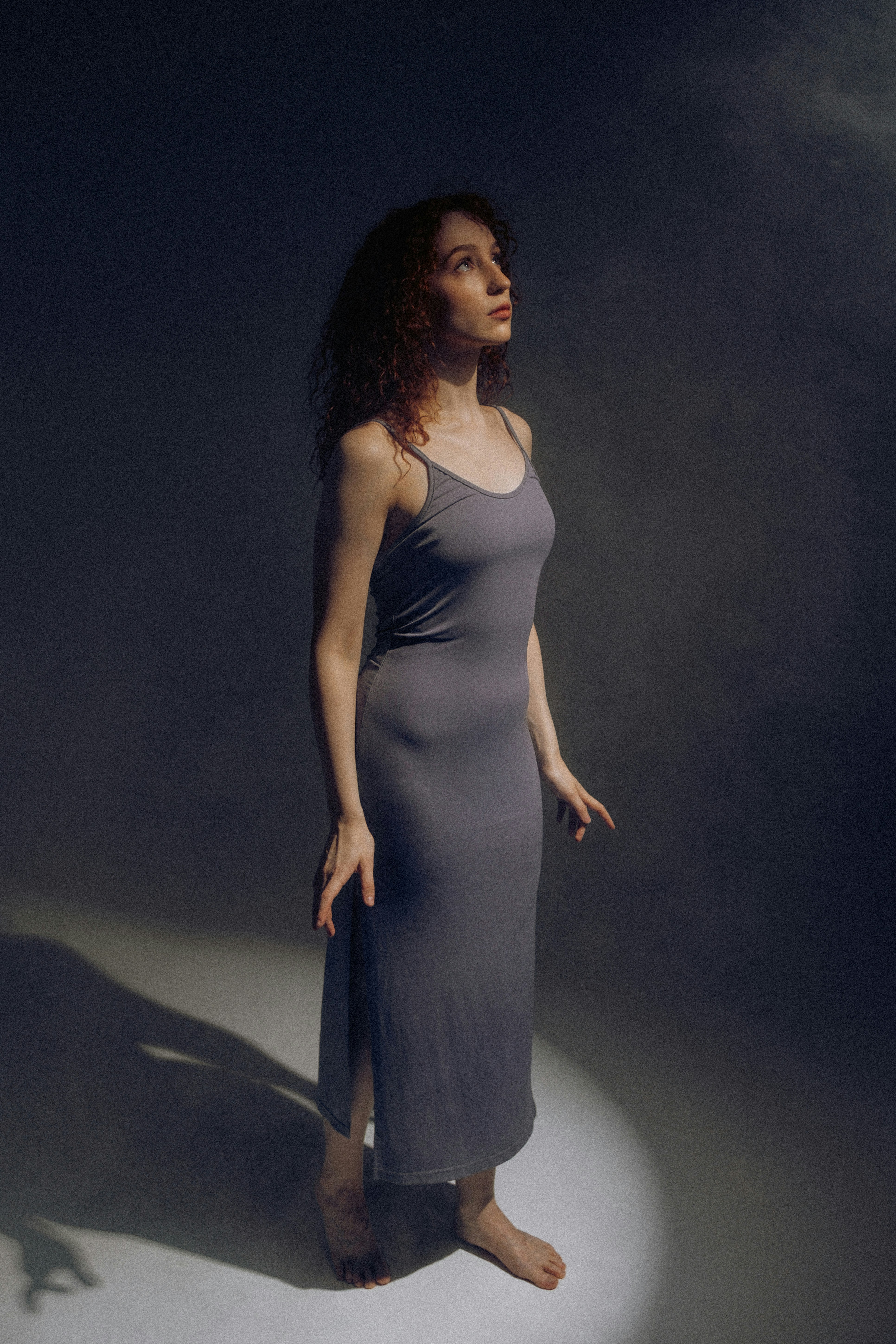 Moonlit Pose: A Women in a Slender Gray Dress Under Subtle Spotlight