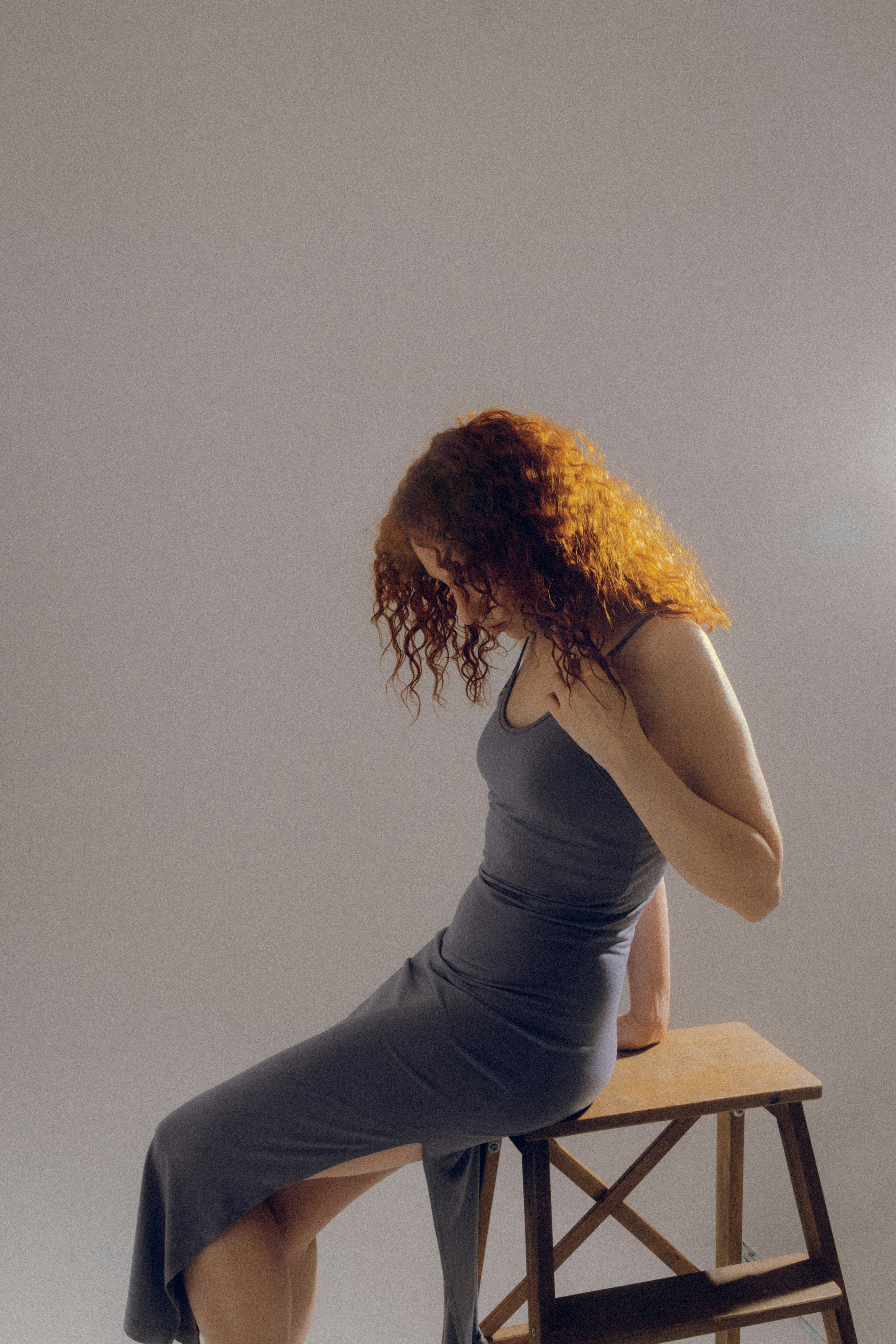 Muted Spotlight: A Quiet Portrait on a Wooden Stool