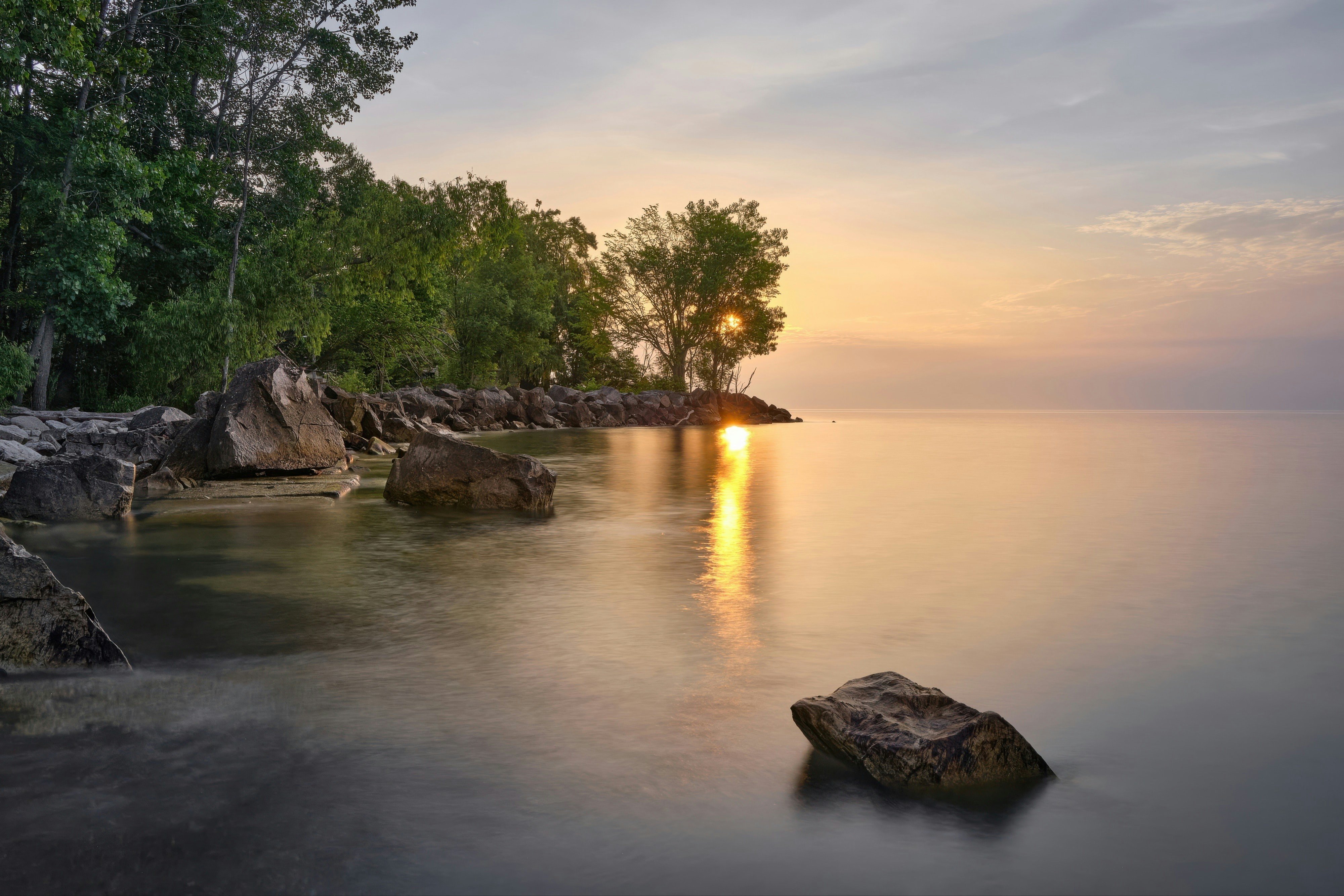 Sunlit Rocks and tranquil water at a lakeside sunset