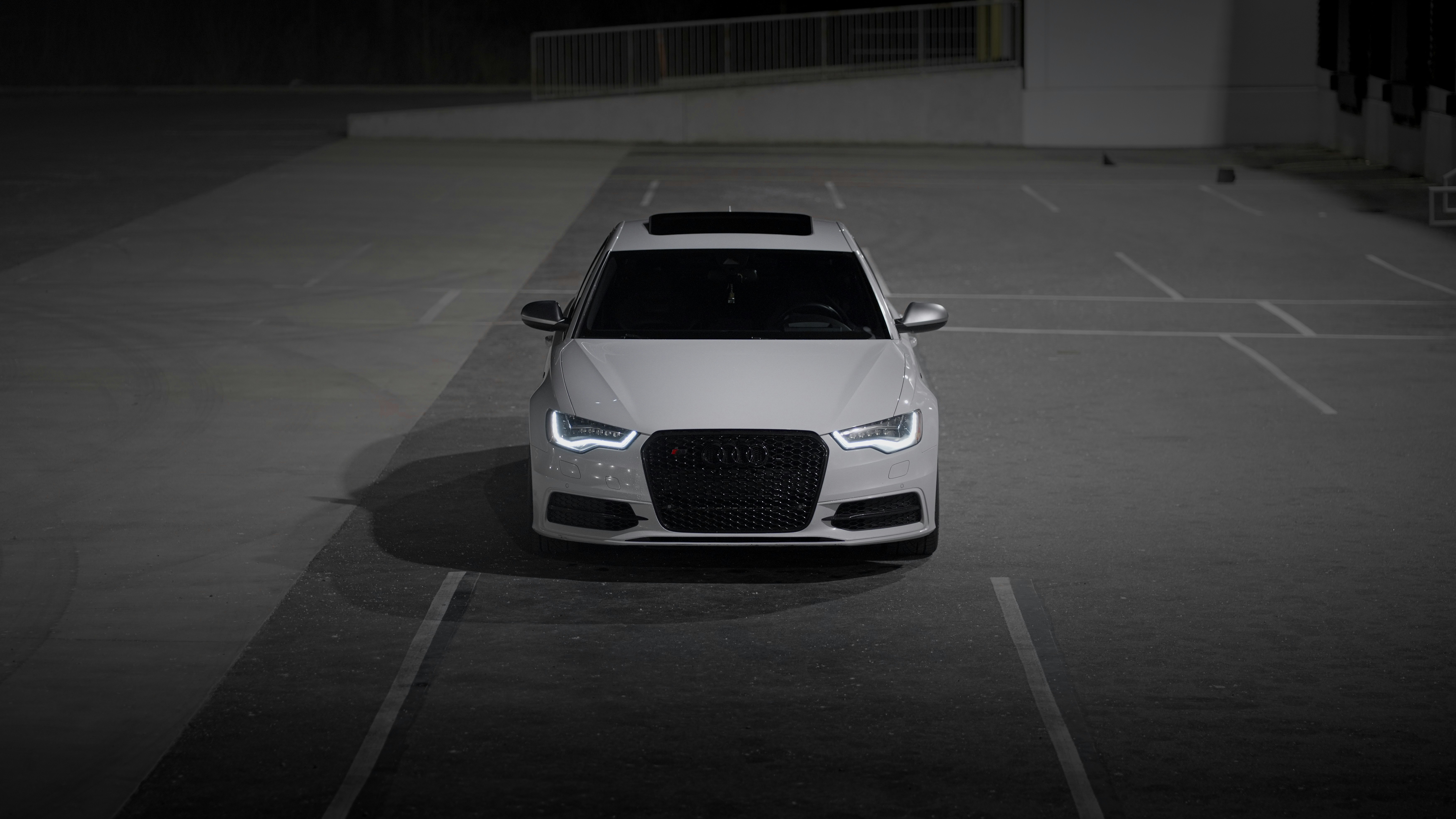 Midnight Spotlight: A White Sedan Centered in a Quiet Parking Lot