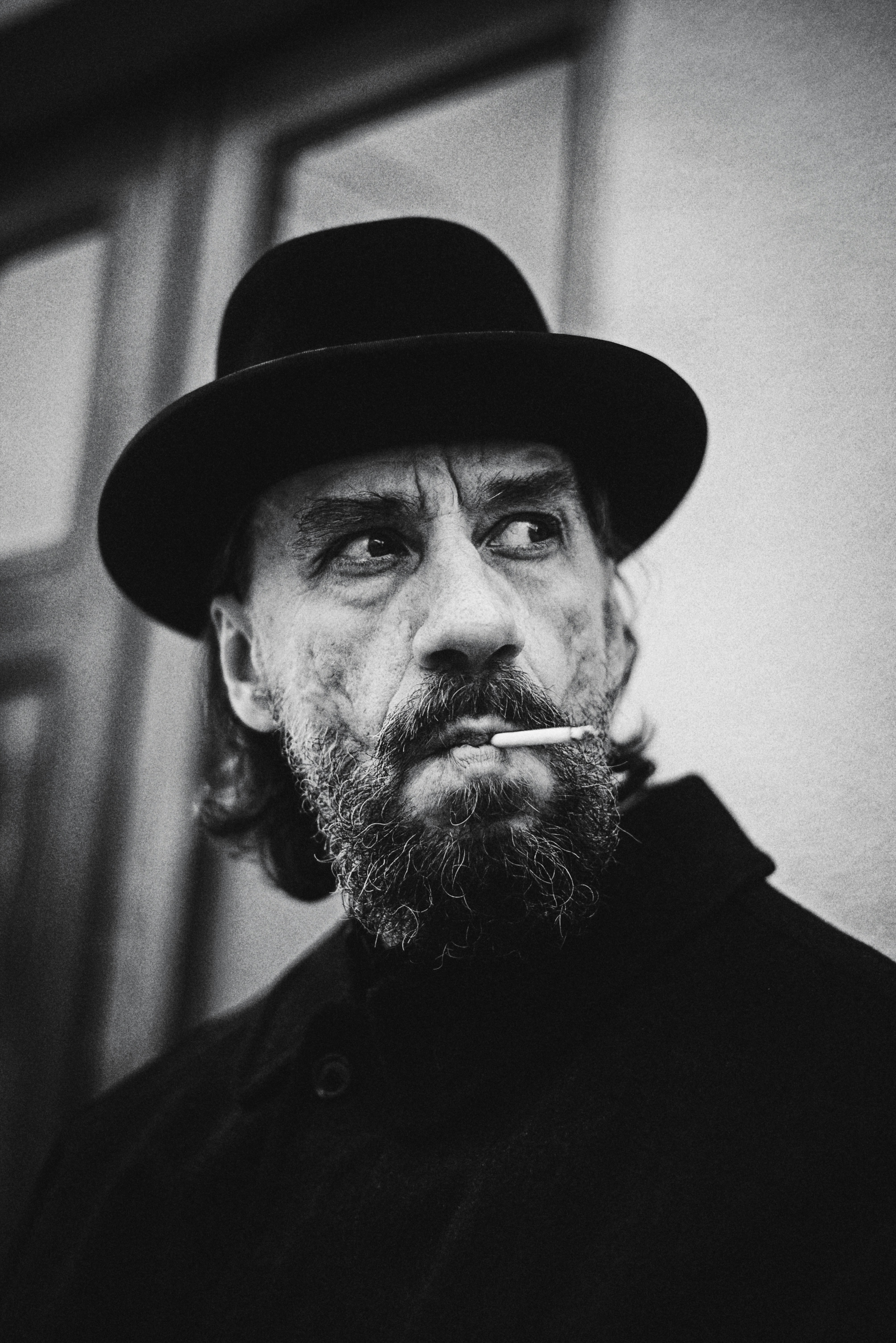 Shadowed Quiet: A Man in a Hat Companionably Smokes in Noir Light