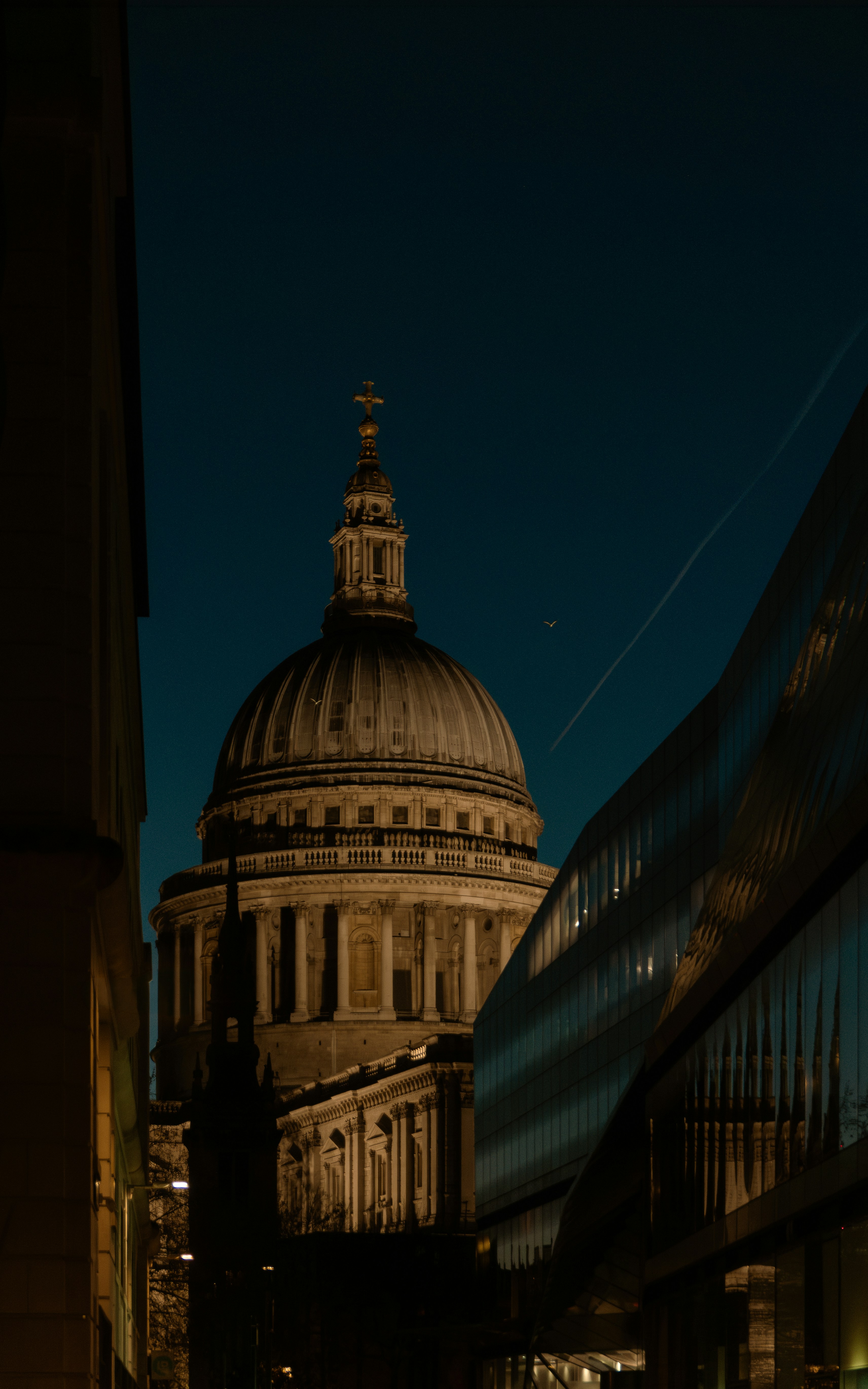 Stately dome under night sky: Westminster-like silhouette between modern rails