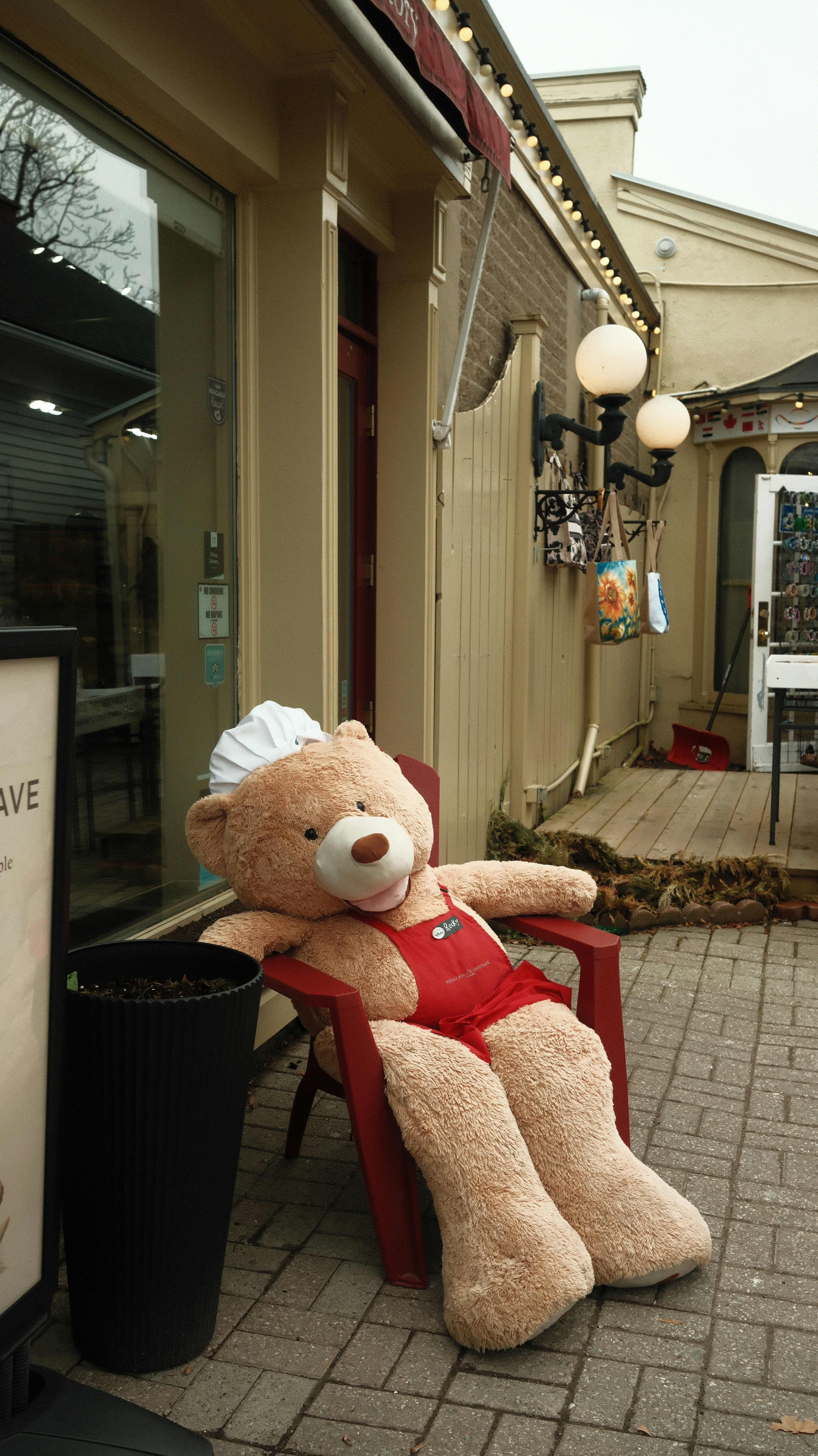 Teddy Bear on a Red Chair Guarding an Outdoor Shopfront