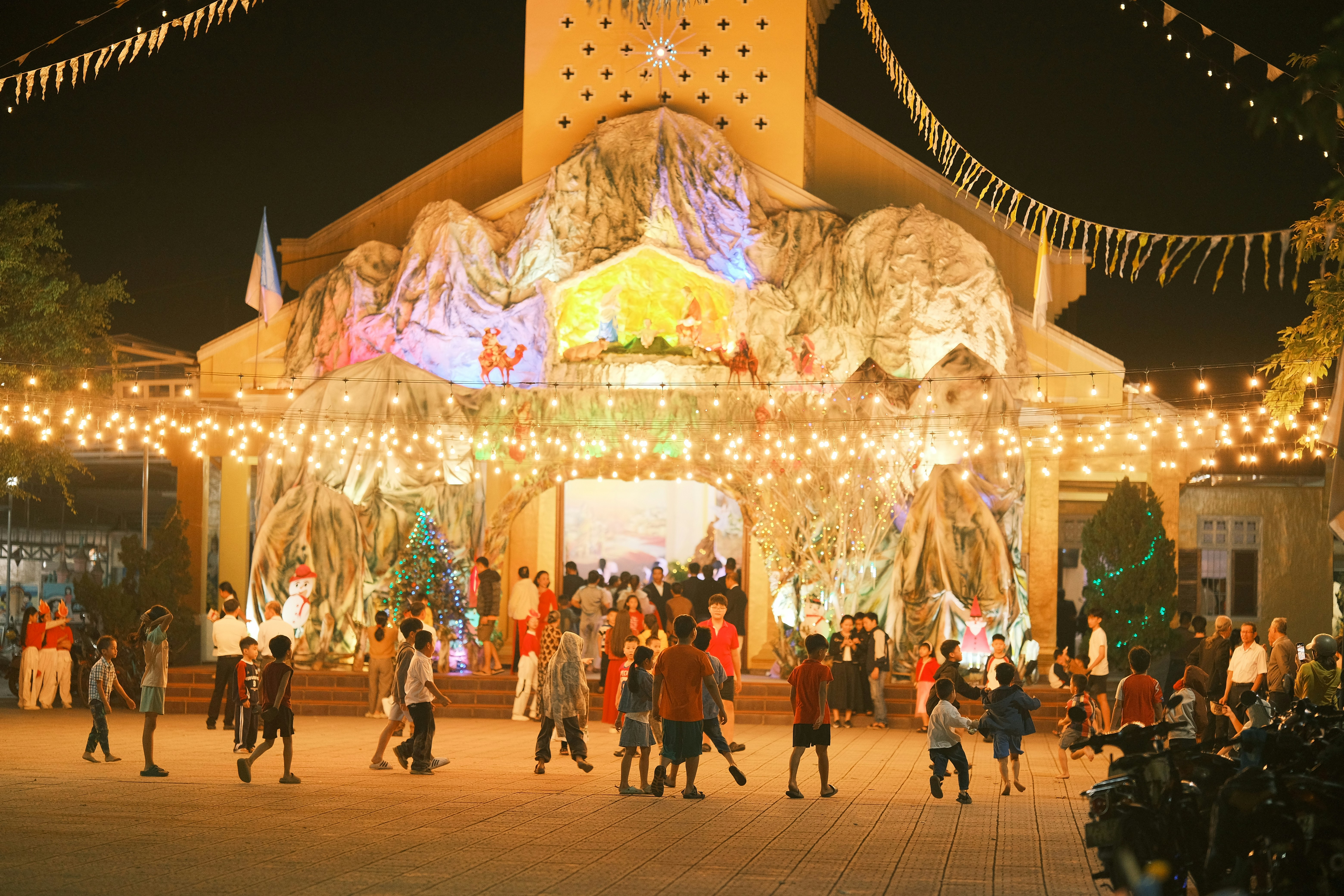 Glowing festival archway: a lantern-lit night crowd under the illuminated venue