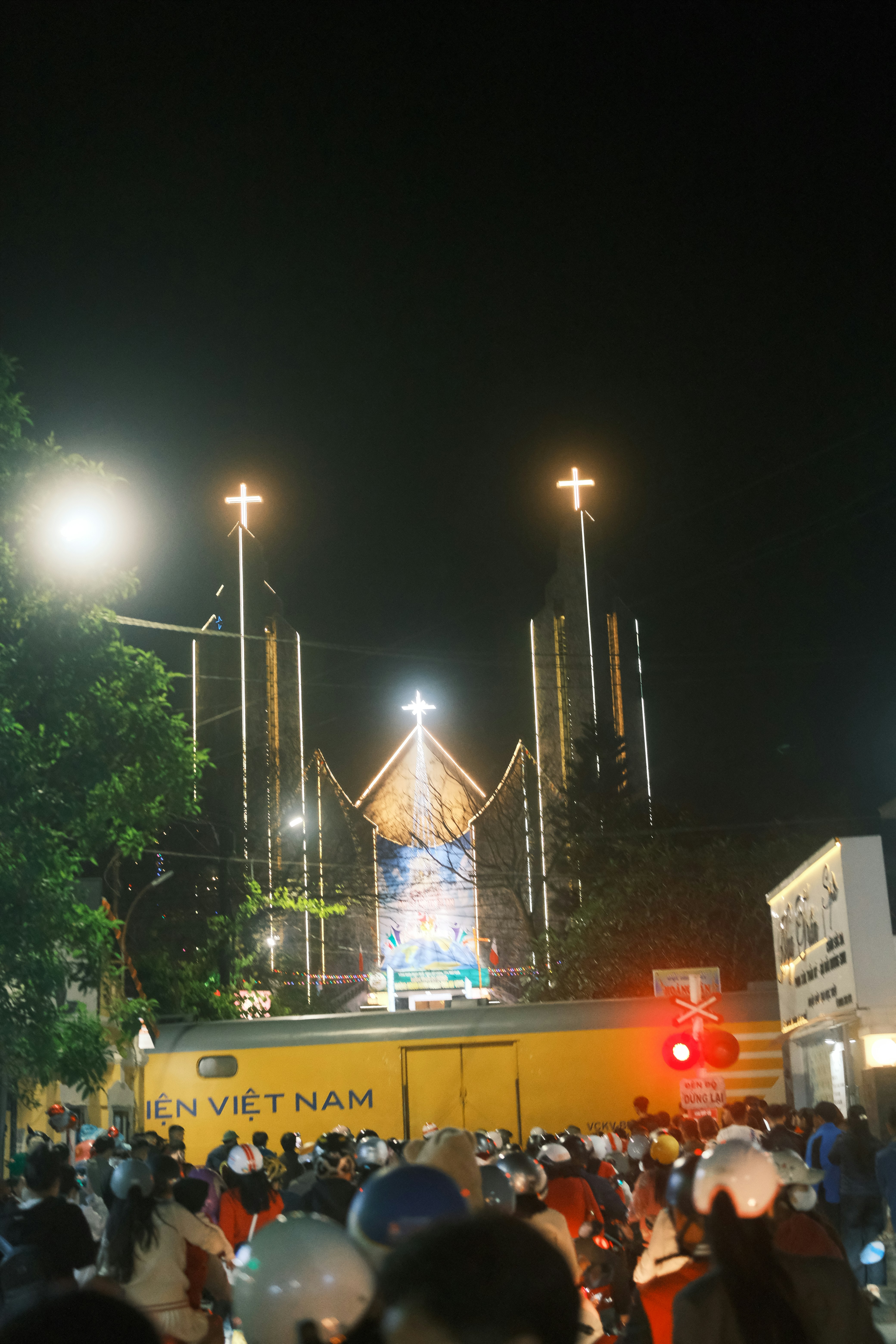 Church illuminated at night with a crowd gathered