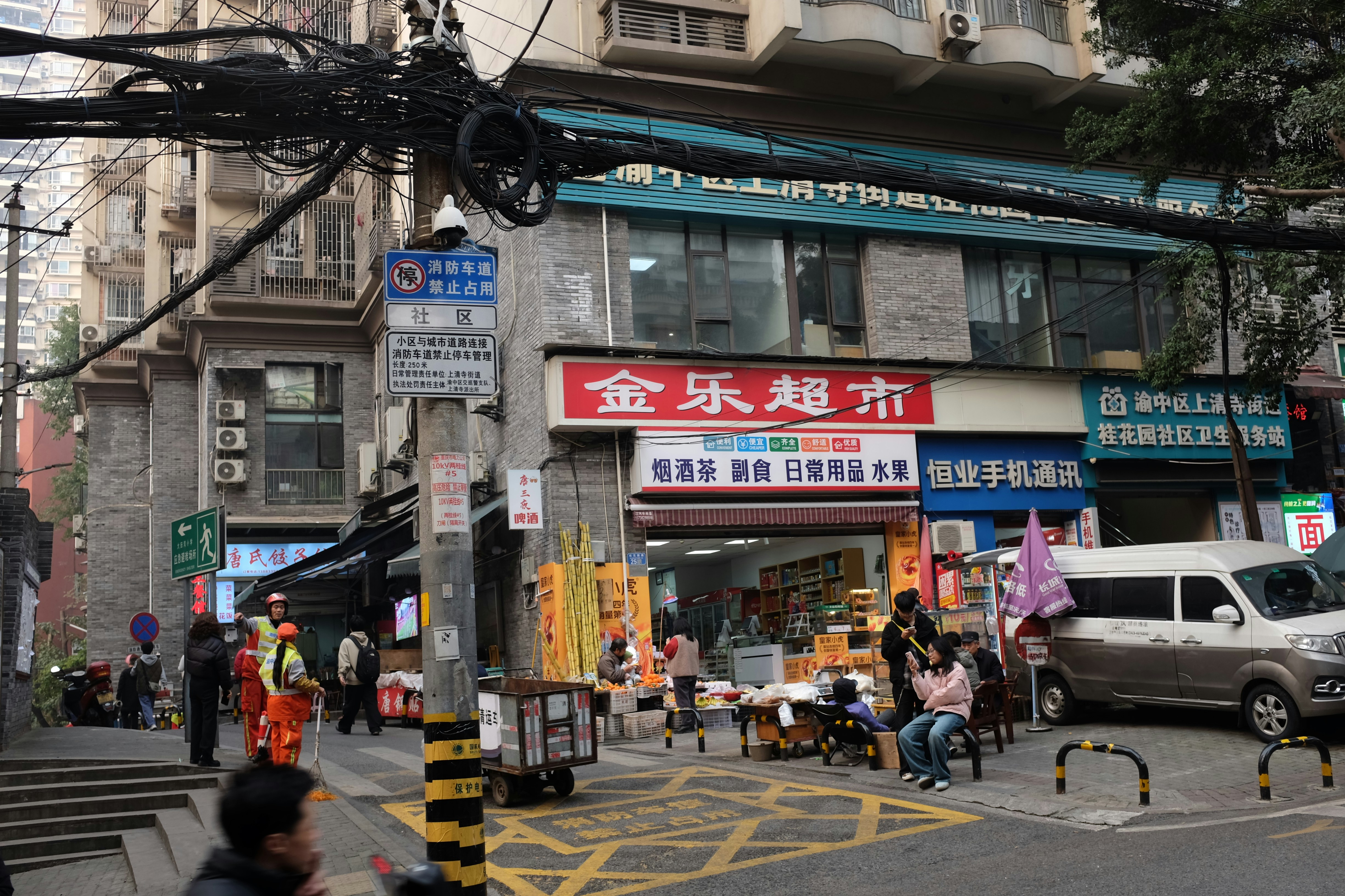 Busy Street Corner with Market Stands under a Tangle of Overhead Wires