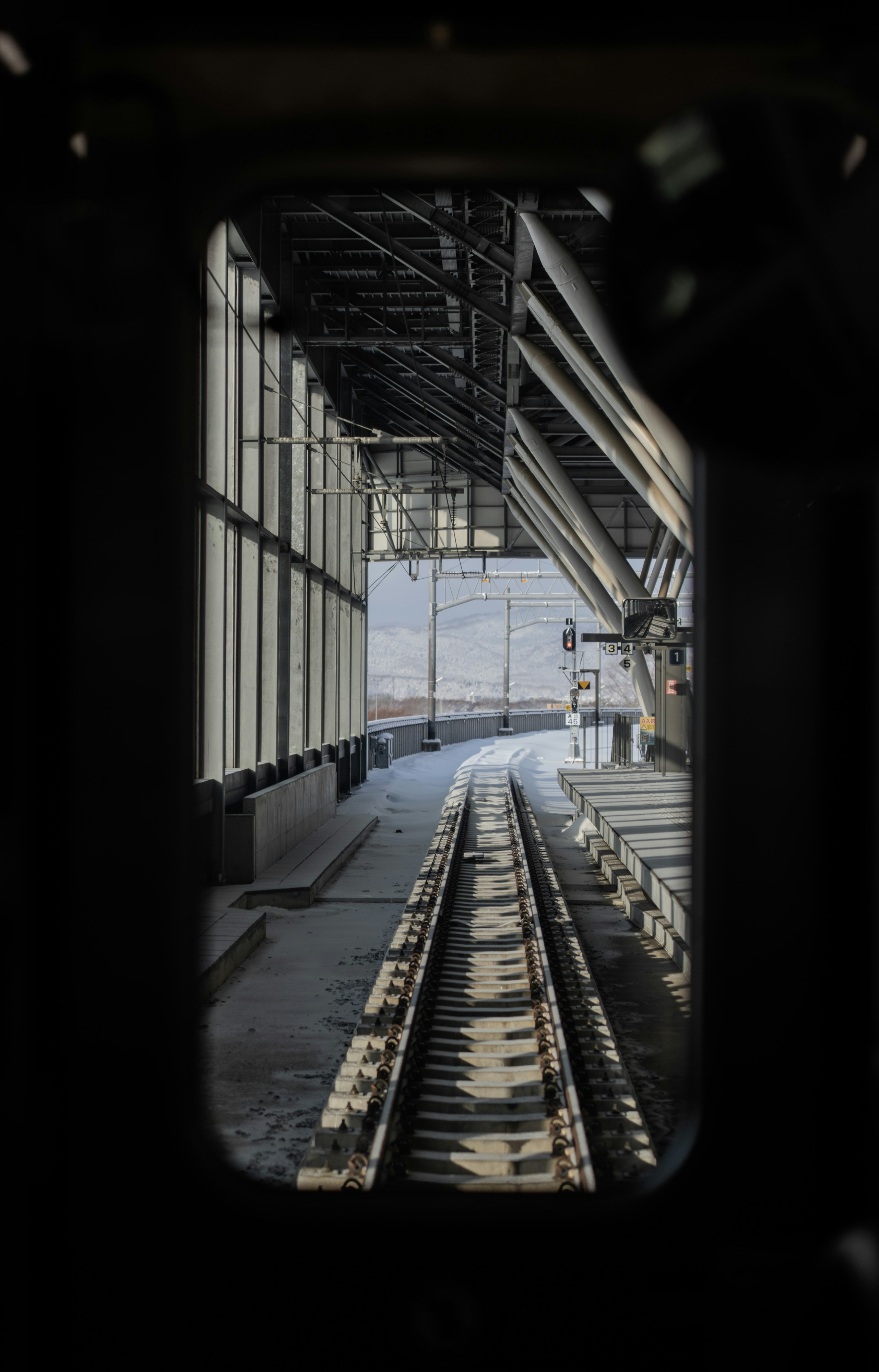 Through the Narrow Frame: rail lines stretching toward cold light