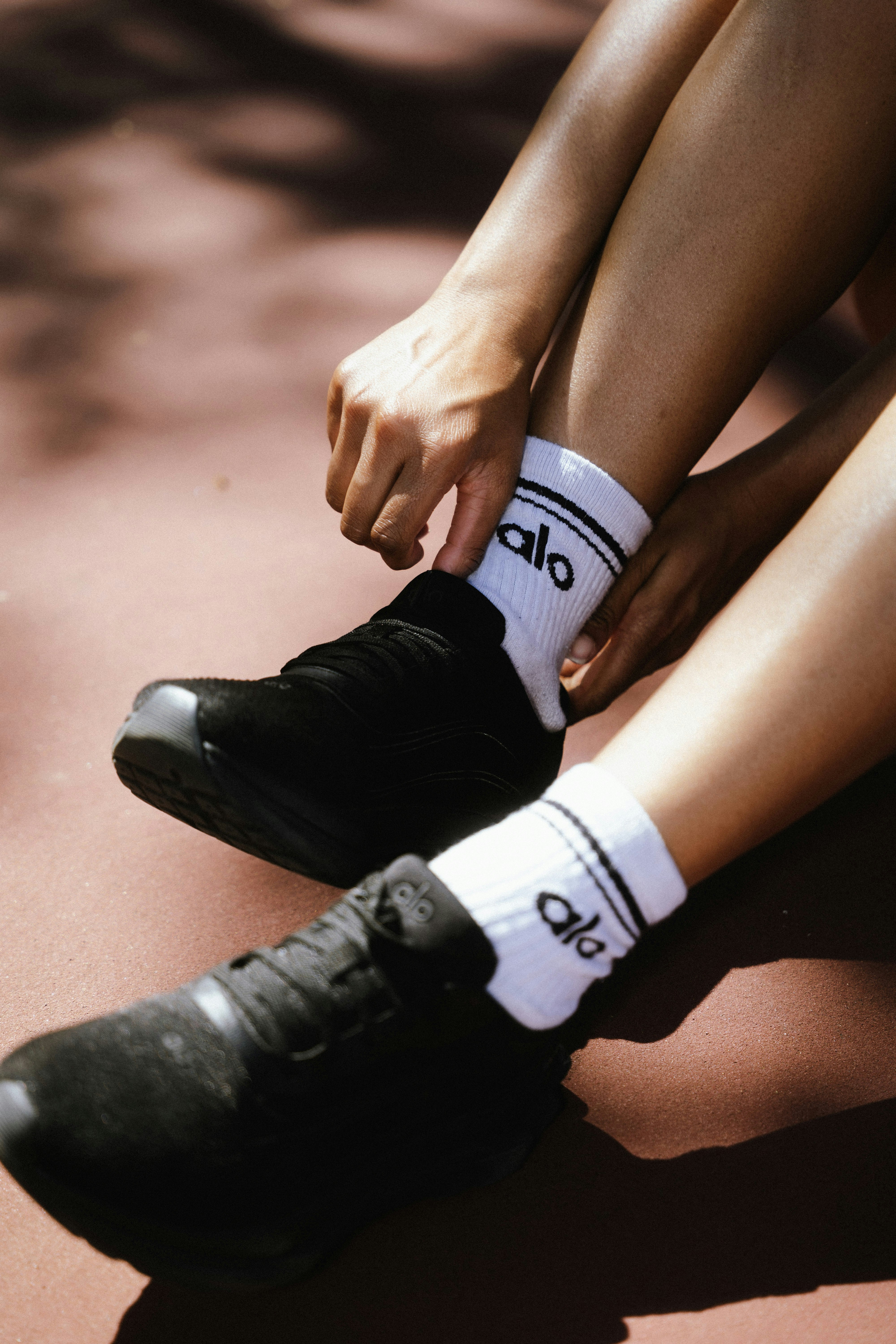 Low-angle sneakers and ankles: a sunlit stride on red court