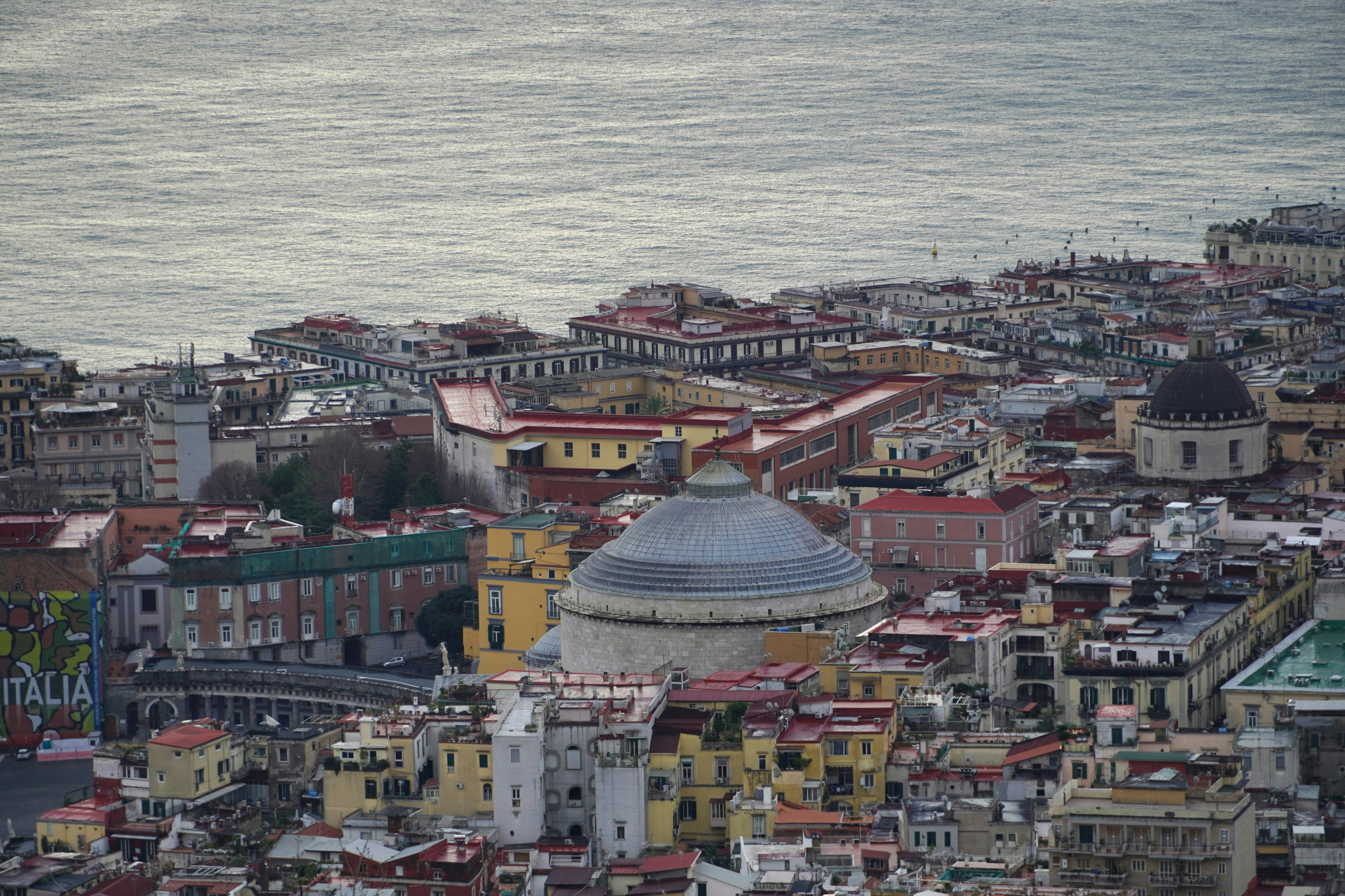 Aerial mosaic of a sunlit Ligurian town with a domed church at center