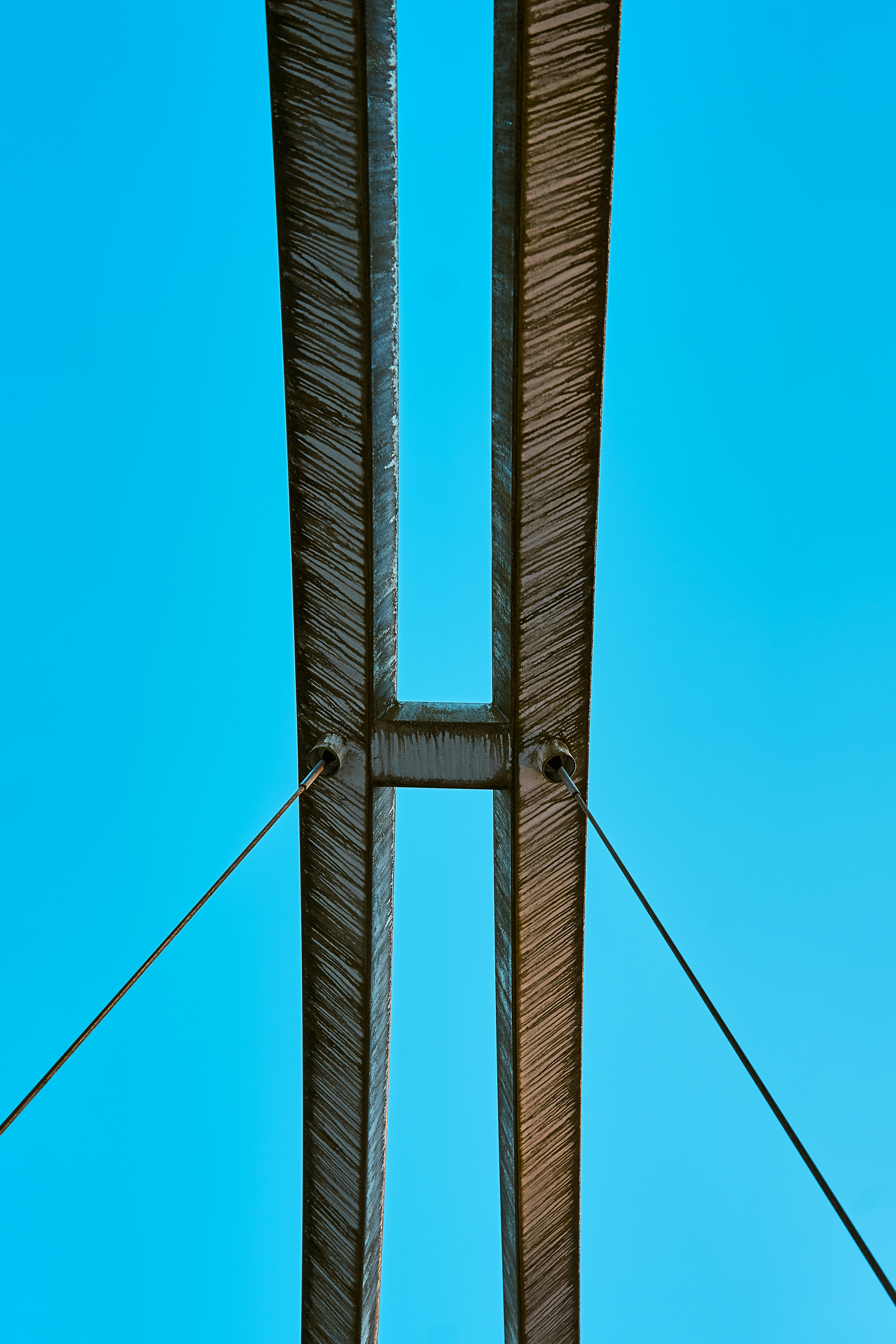 Two parallel steel beams frame a vivid cobalt sky, creating a minimal, architectural composition with dramatic negative space.