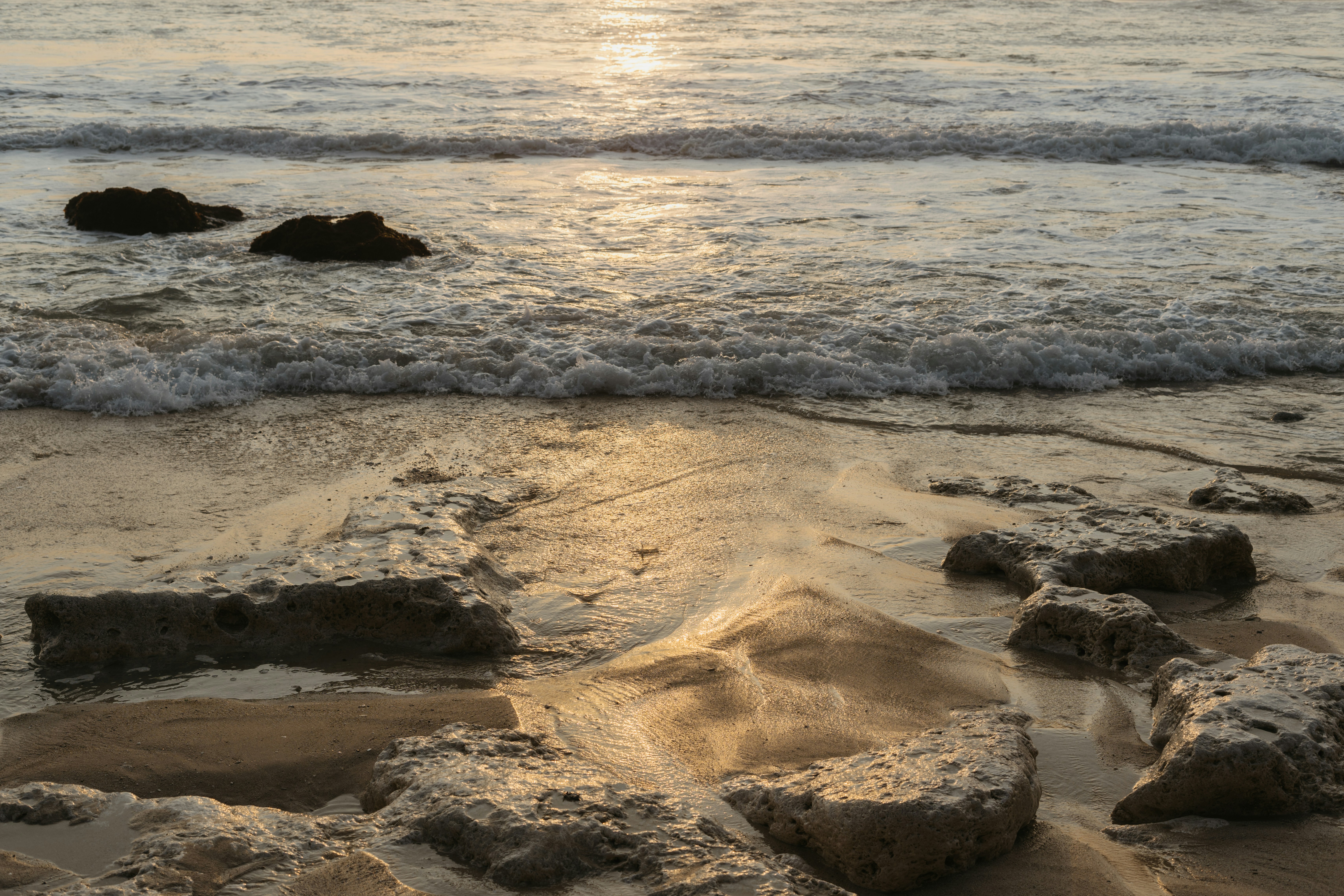 Golden Ripples: Tidelit Sand Between Weathered Rocks