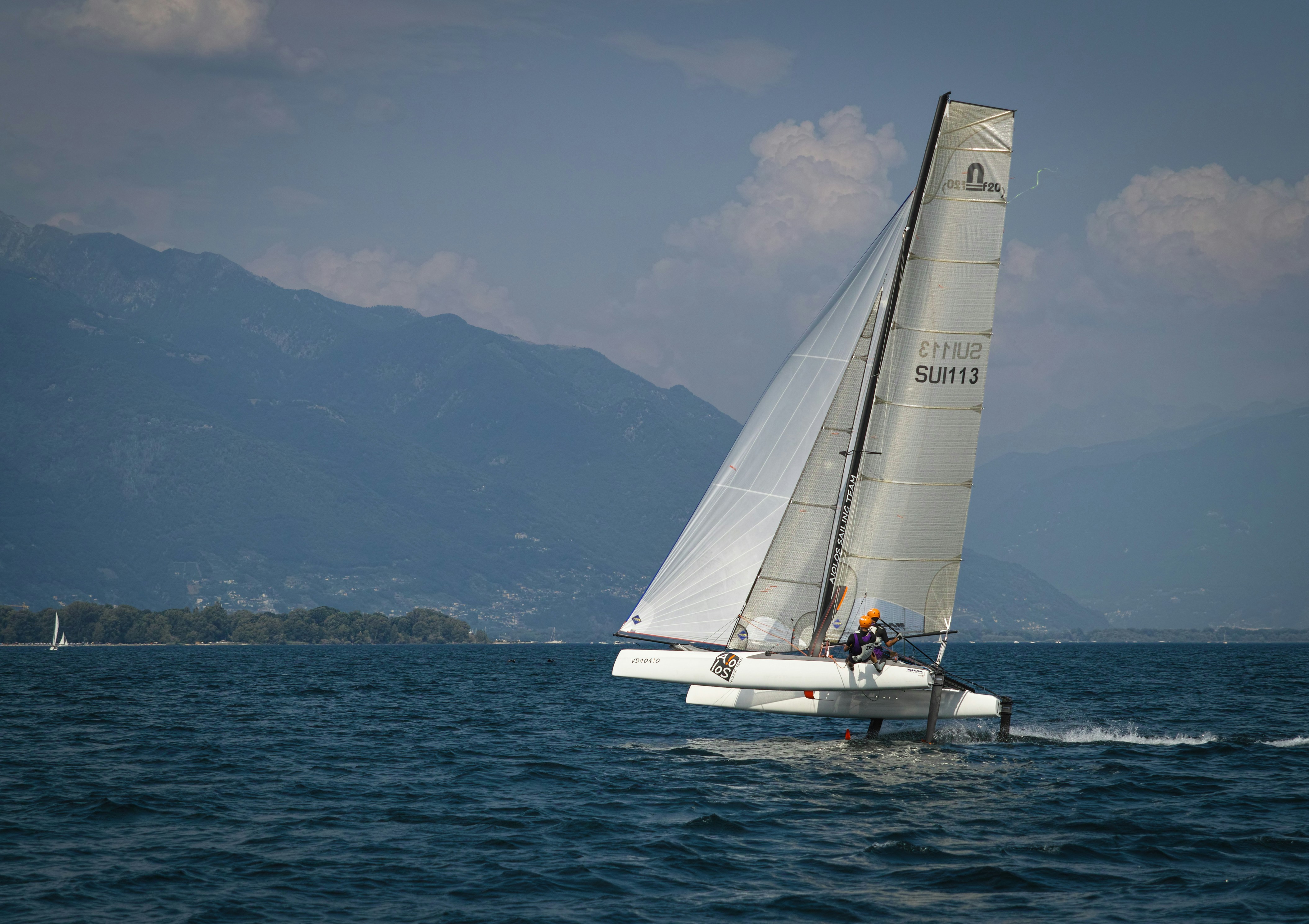 Sailboat in sunlit lake with alpine backdrop