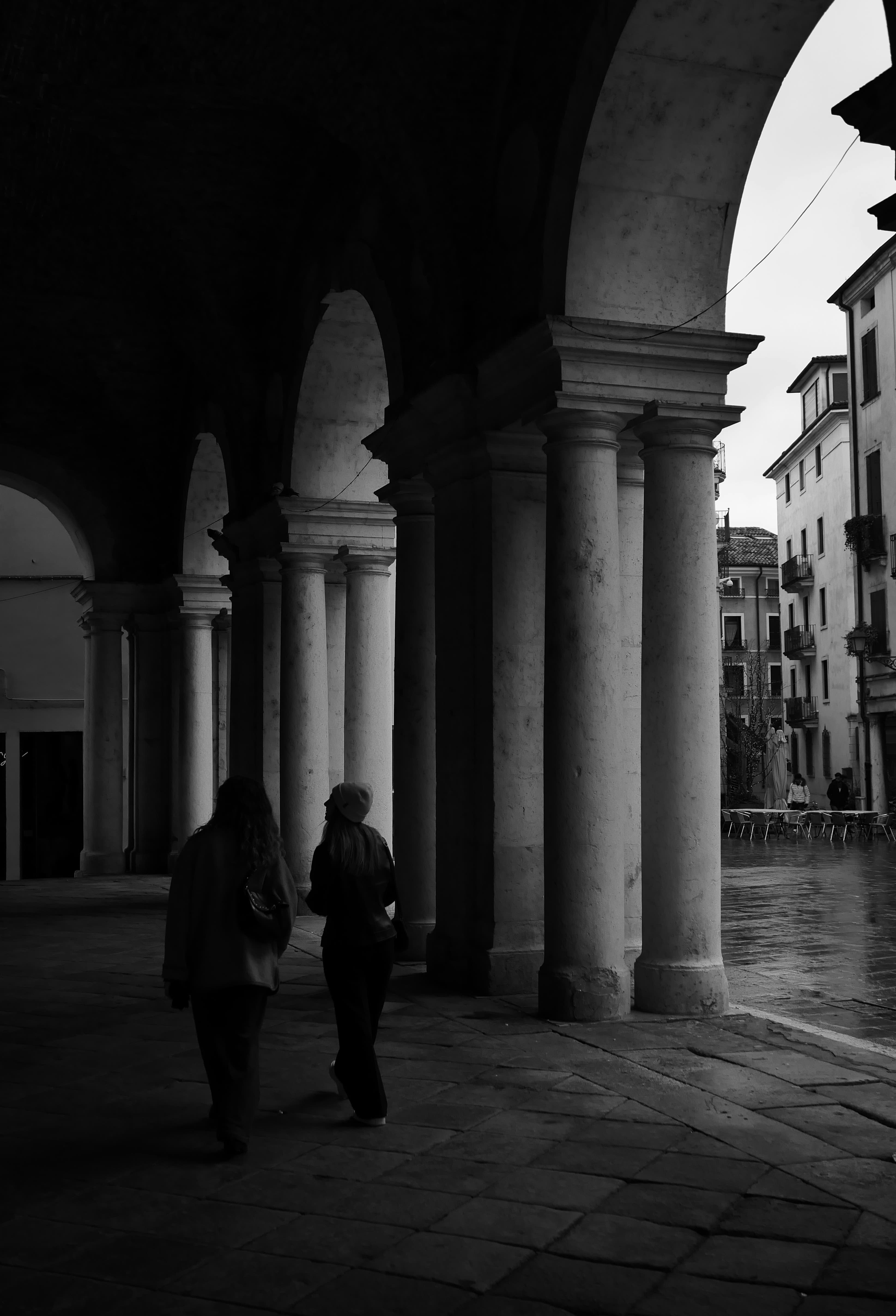 Shadows under the Colonnade: Two Walkers in a Monochrome Arc