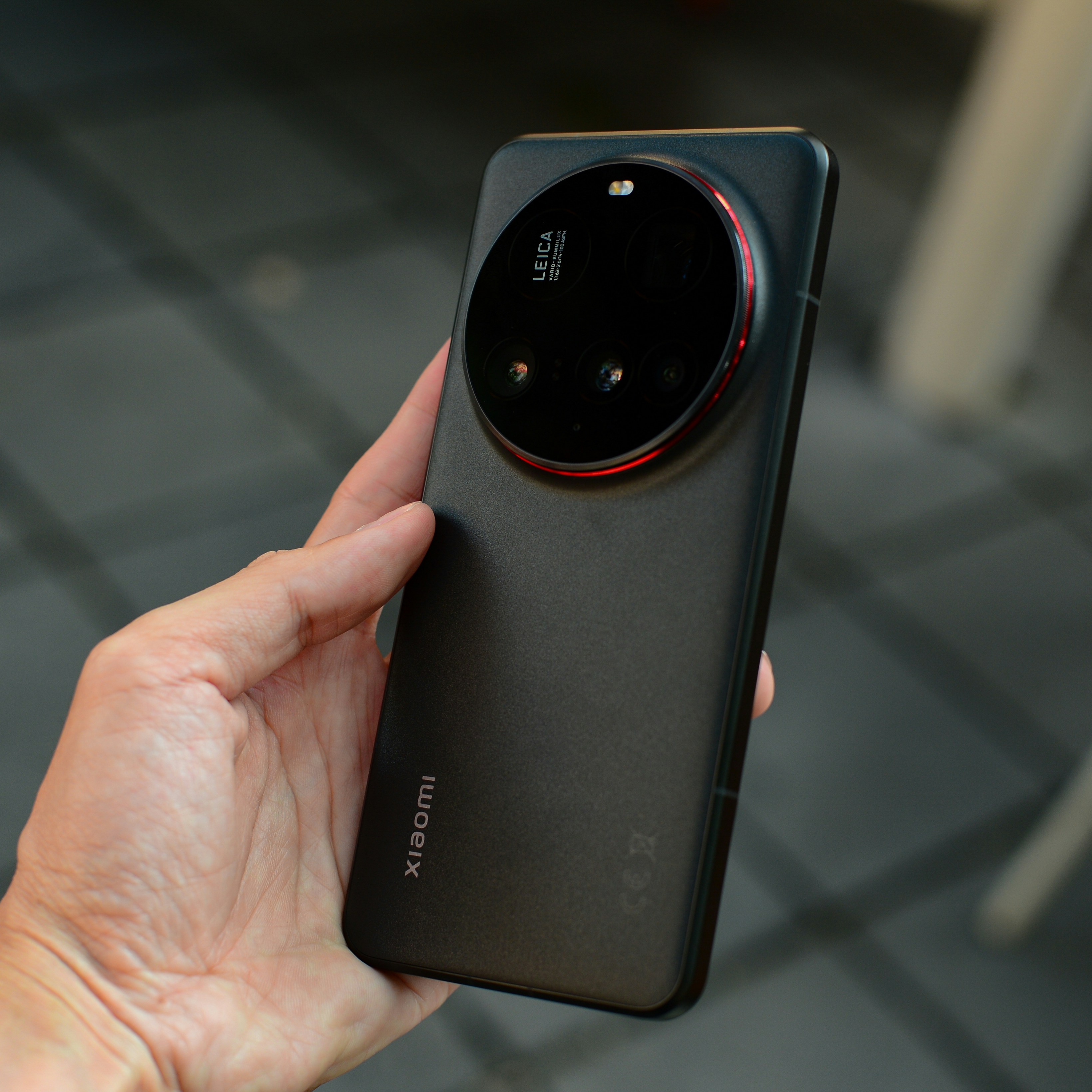 Portrait of a Leica-tinted Shadow: Holding a Modern Smartphone with a Circular Camera Module