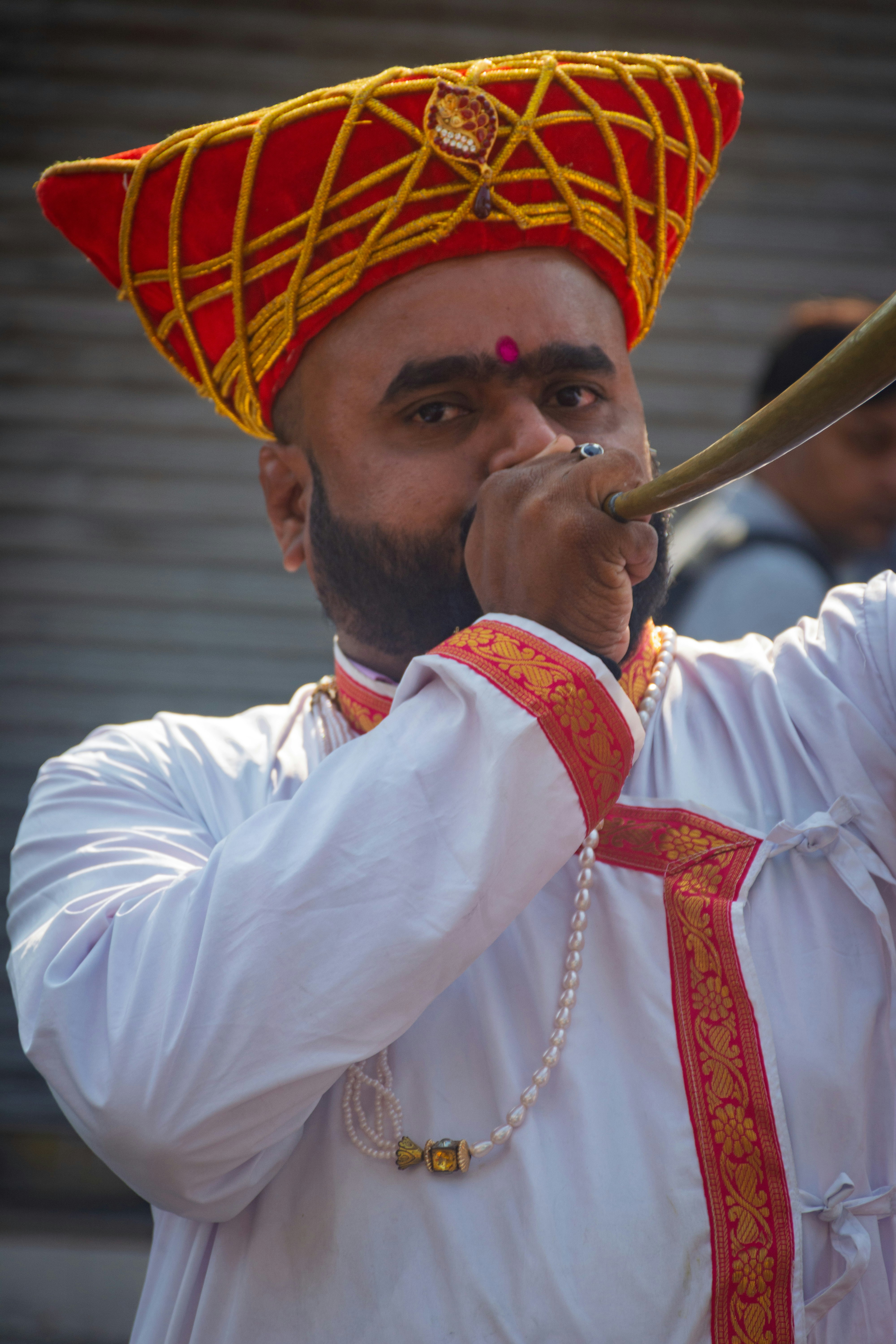 Headgear and Horn: A ceremonial hornblower in vibrant attire
