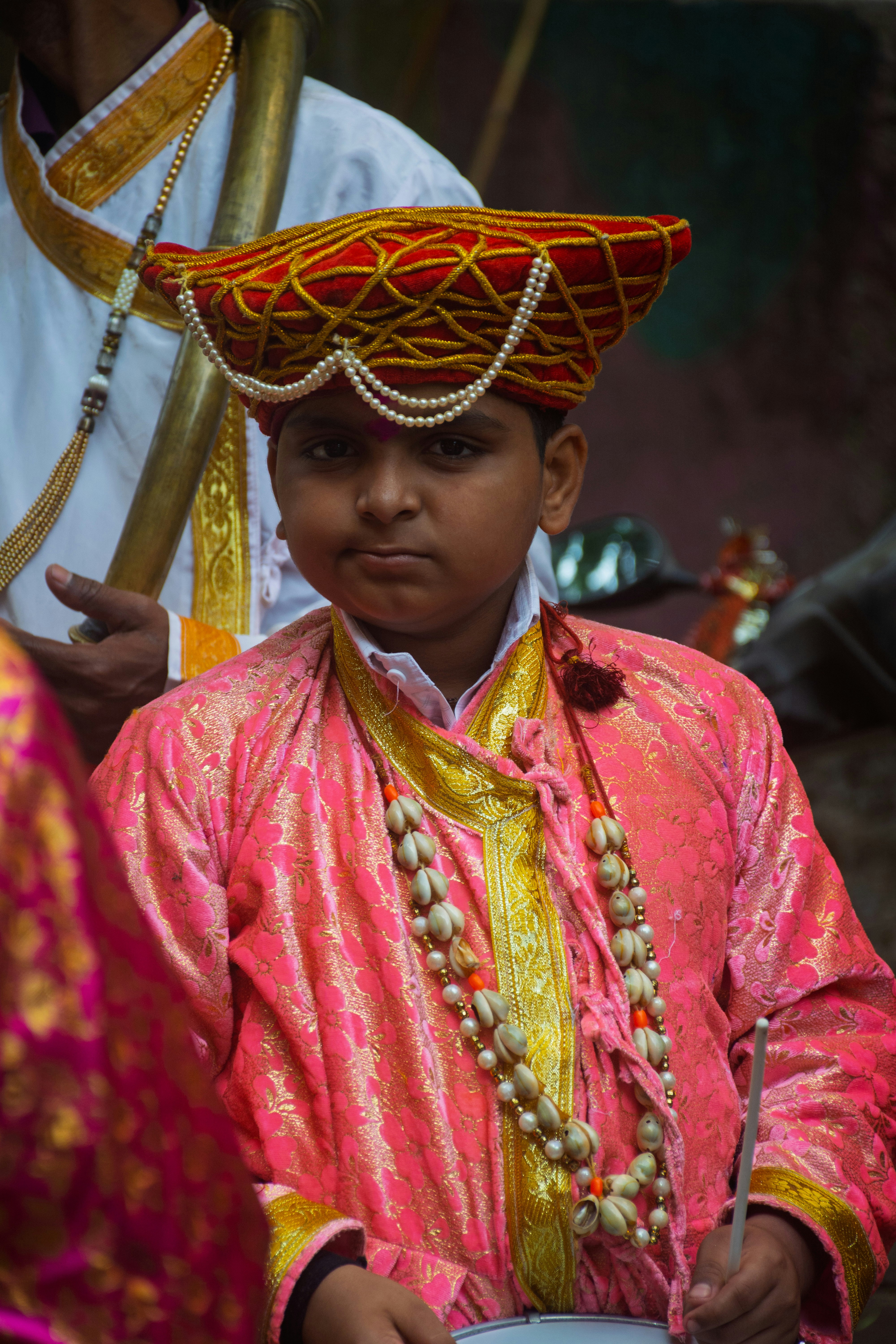 Bright ceremonial robe and pearl garlands frame a young participant in a vibrant cultural procession