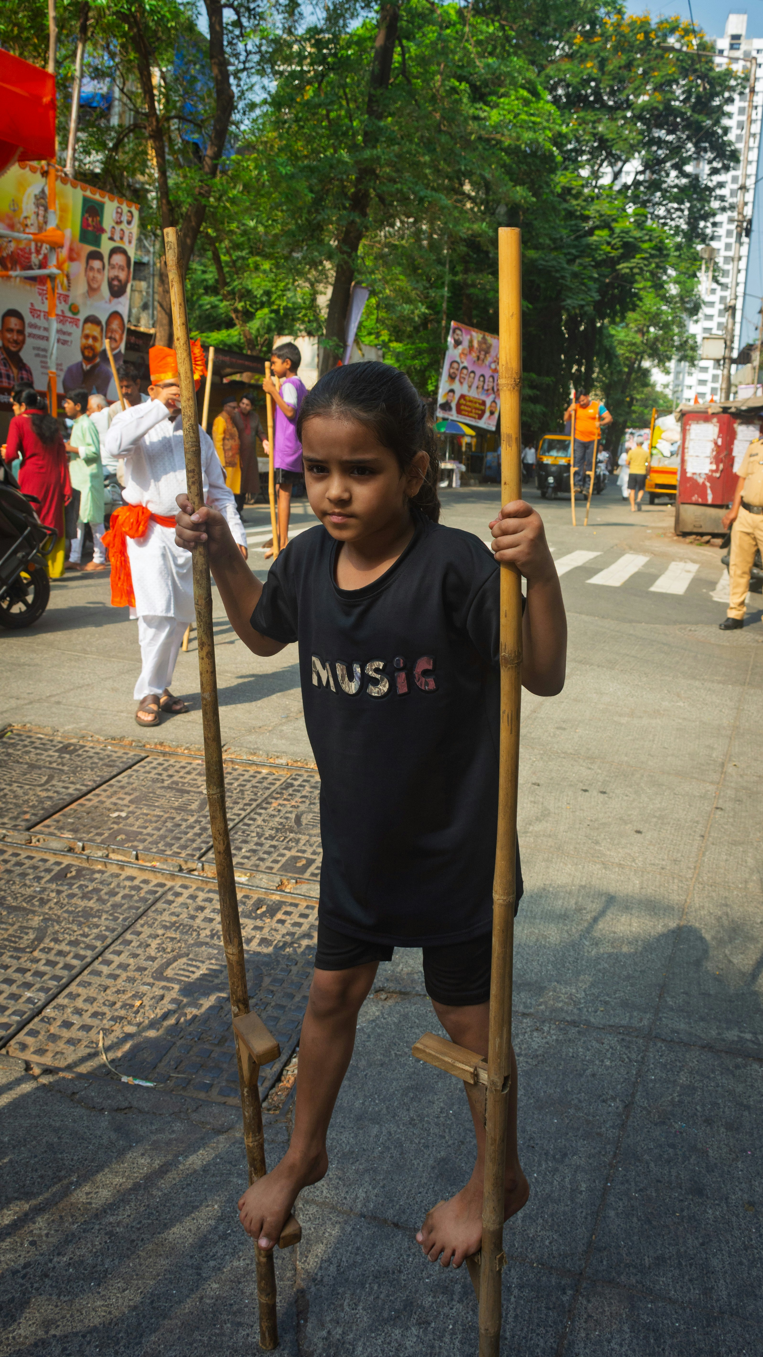 Girl balancing on wooden stilts during a street festival
