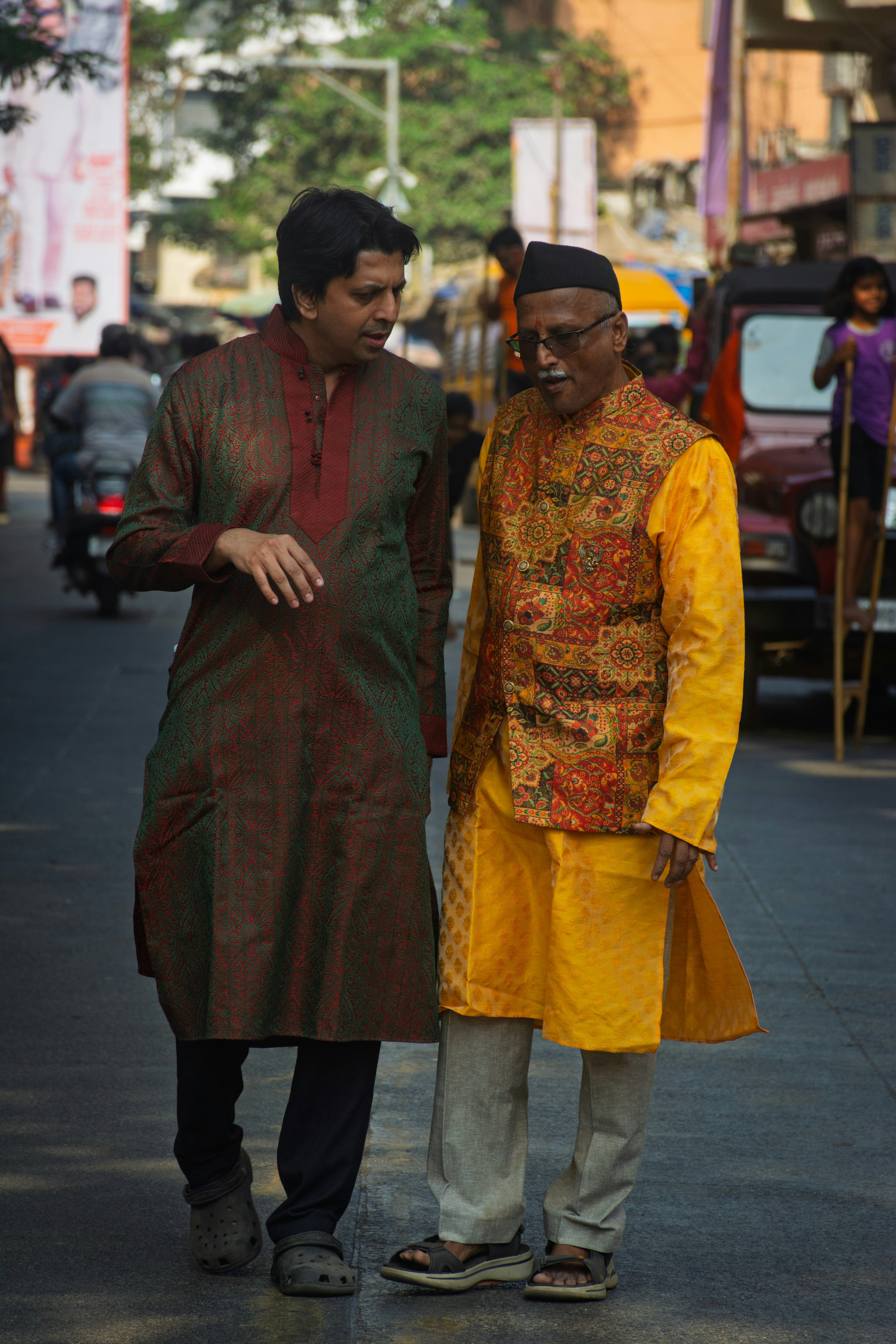 Two Travelers in Colorful Indian Attire Share a Moment on a Busy Street