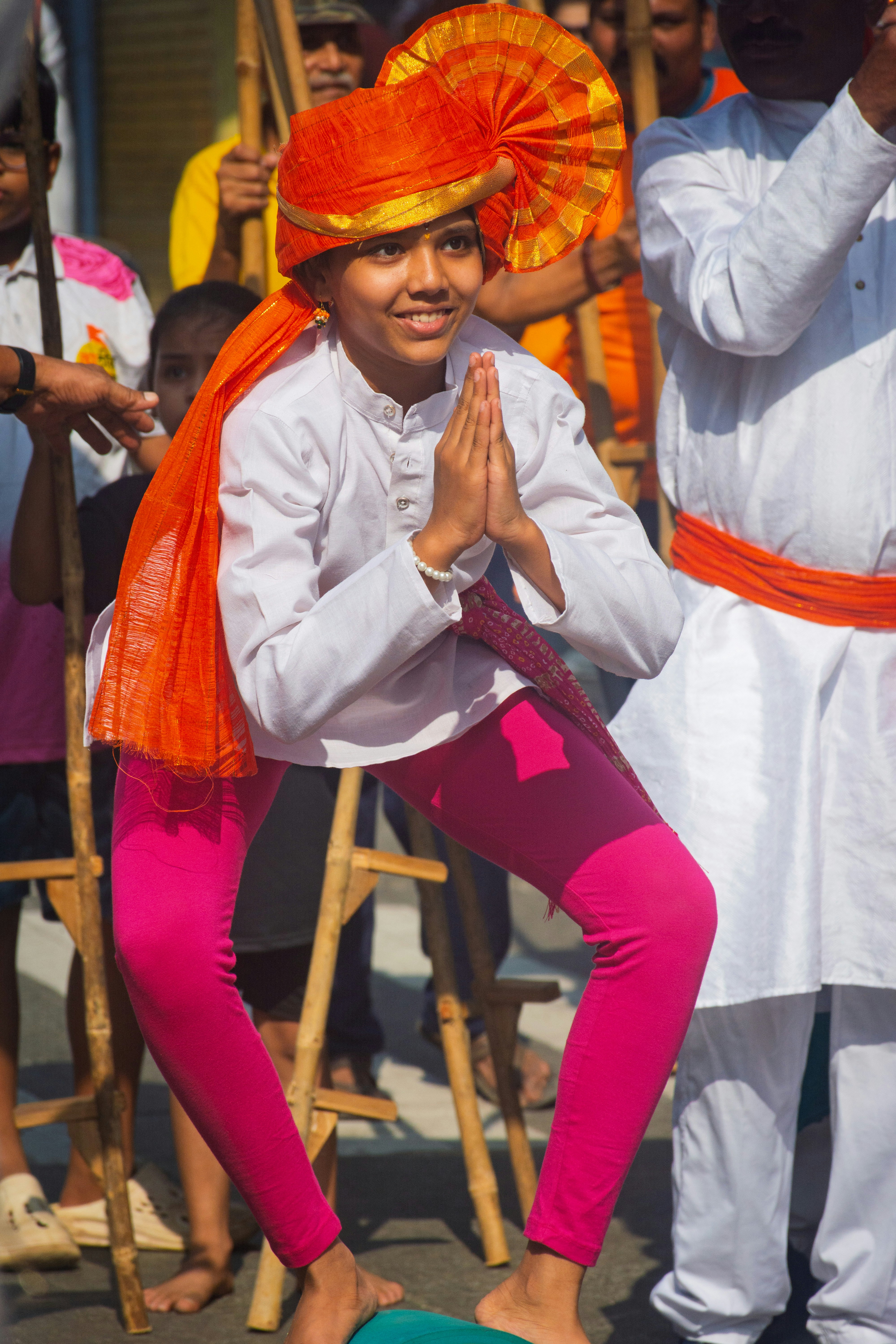 Prayerful Pose on Bright Stage: A Young Dancer in Orange Turban