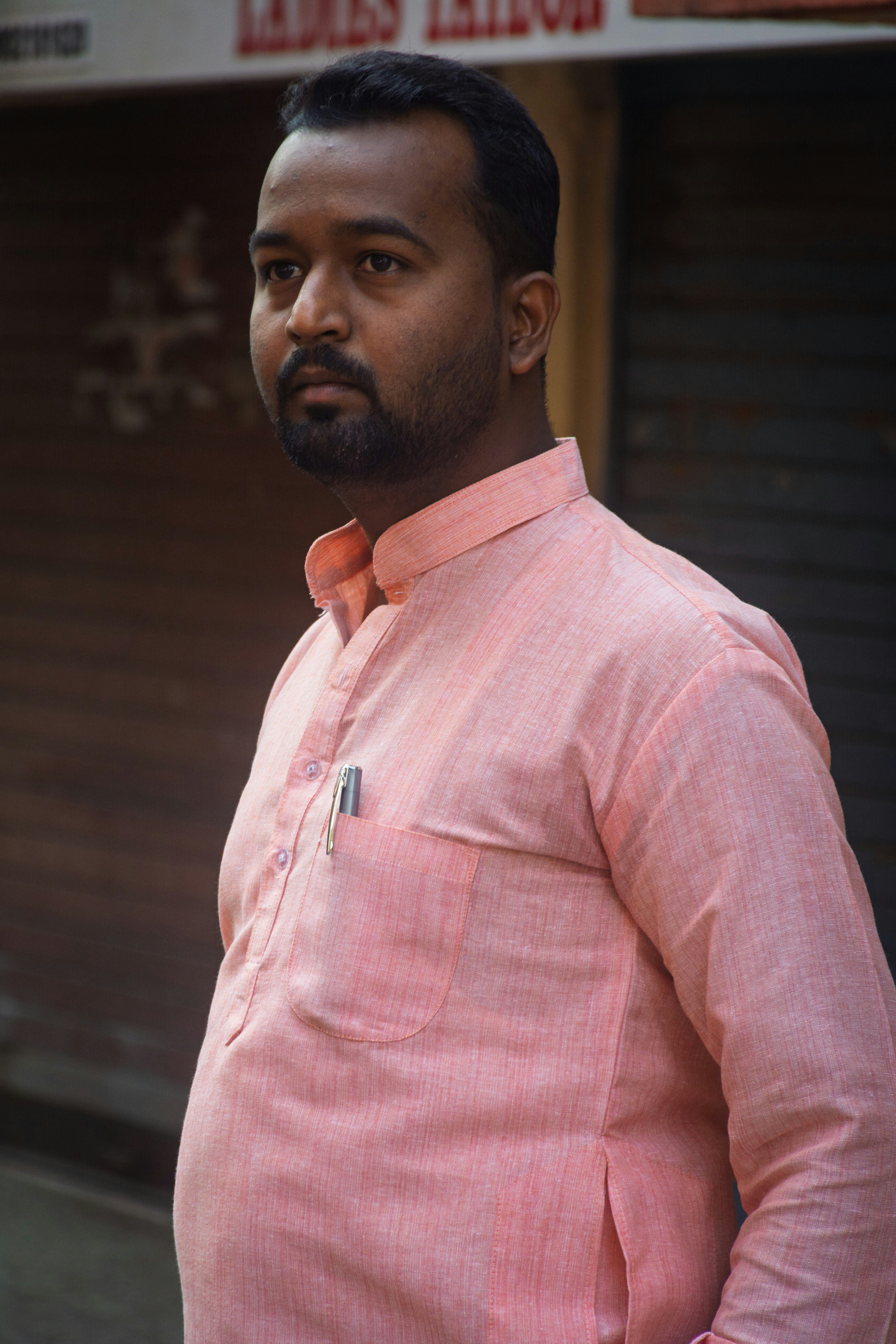 Portrait in warm peach: a thoughtful gaze against a muted street backdrop