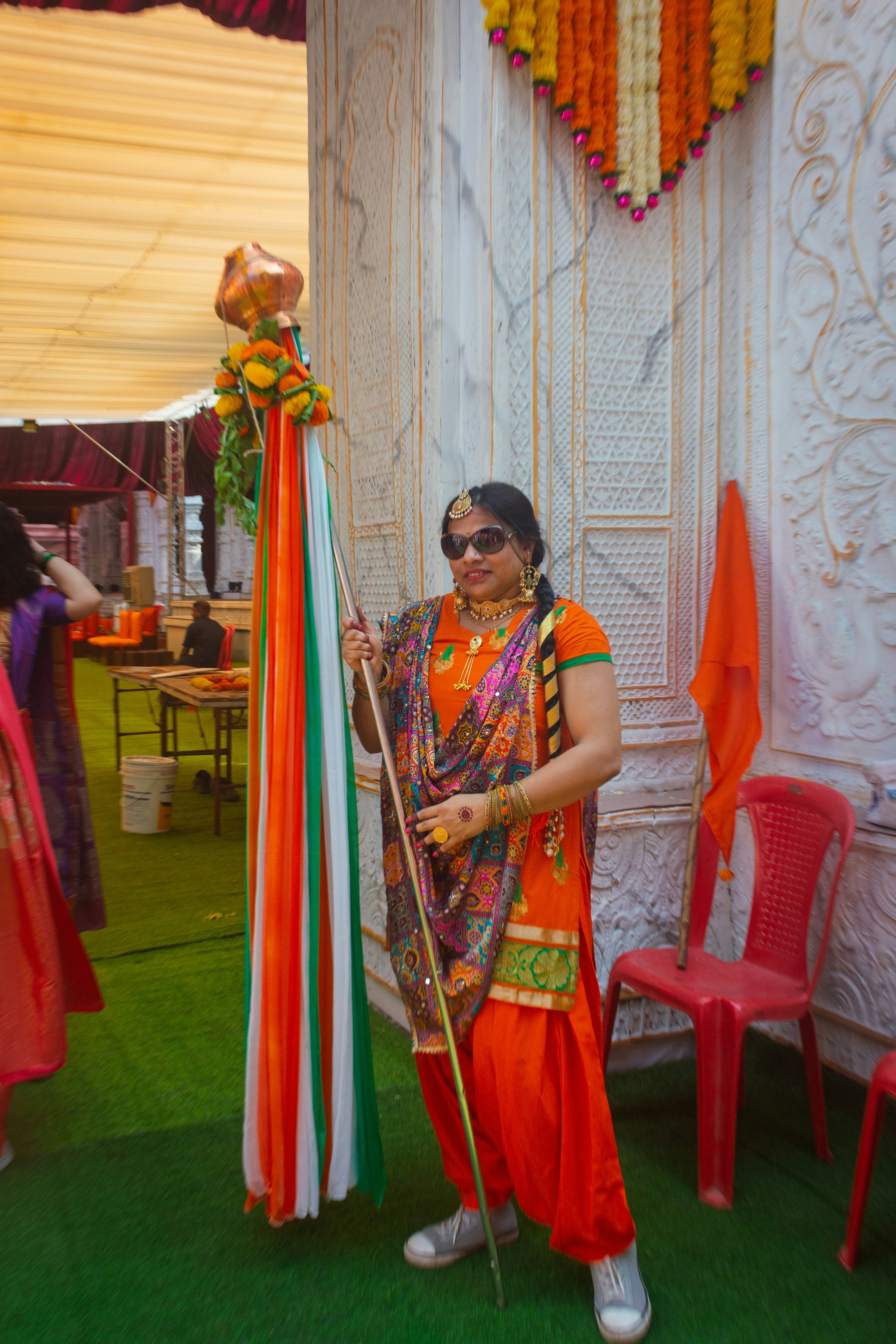 Vibrant festival garb and ceremonial staff in front of carved ceremonial backdrop