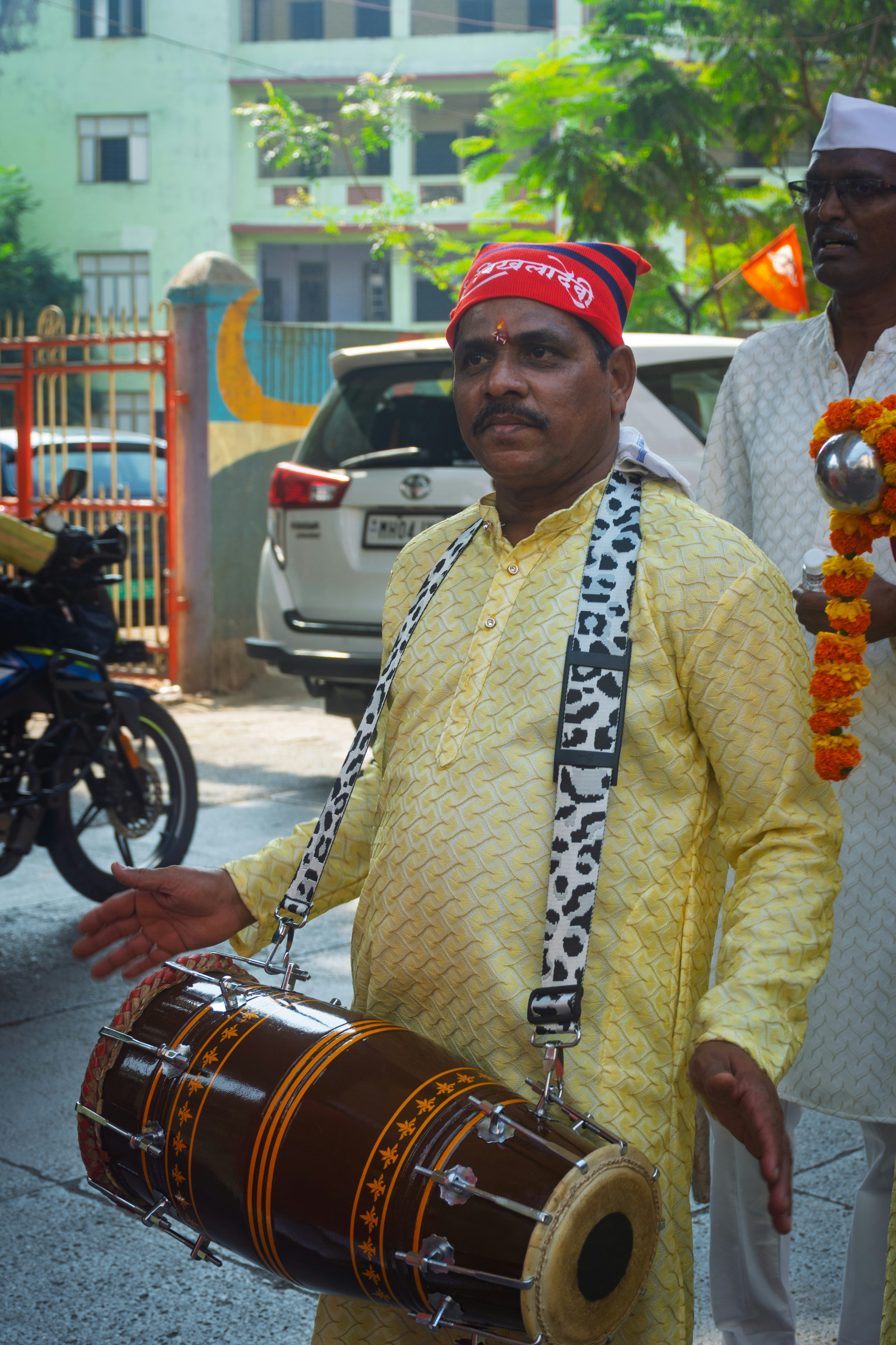 Bandurist in yellow sherwani leads procession with dhol in a sunny street