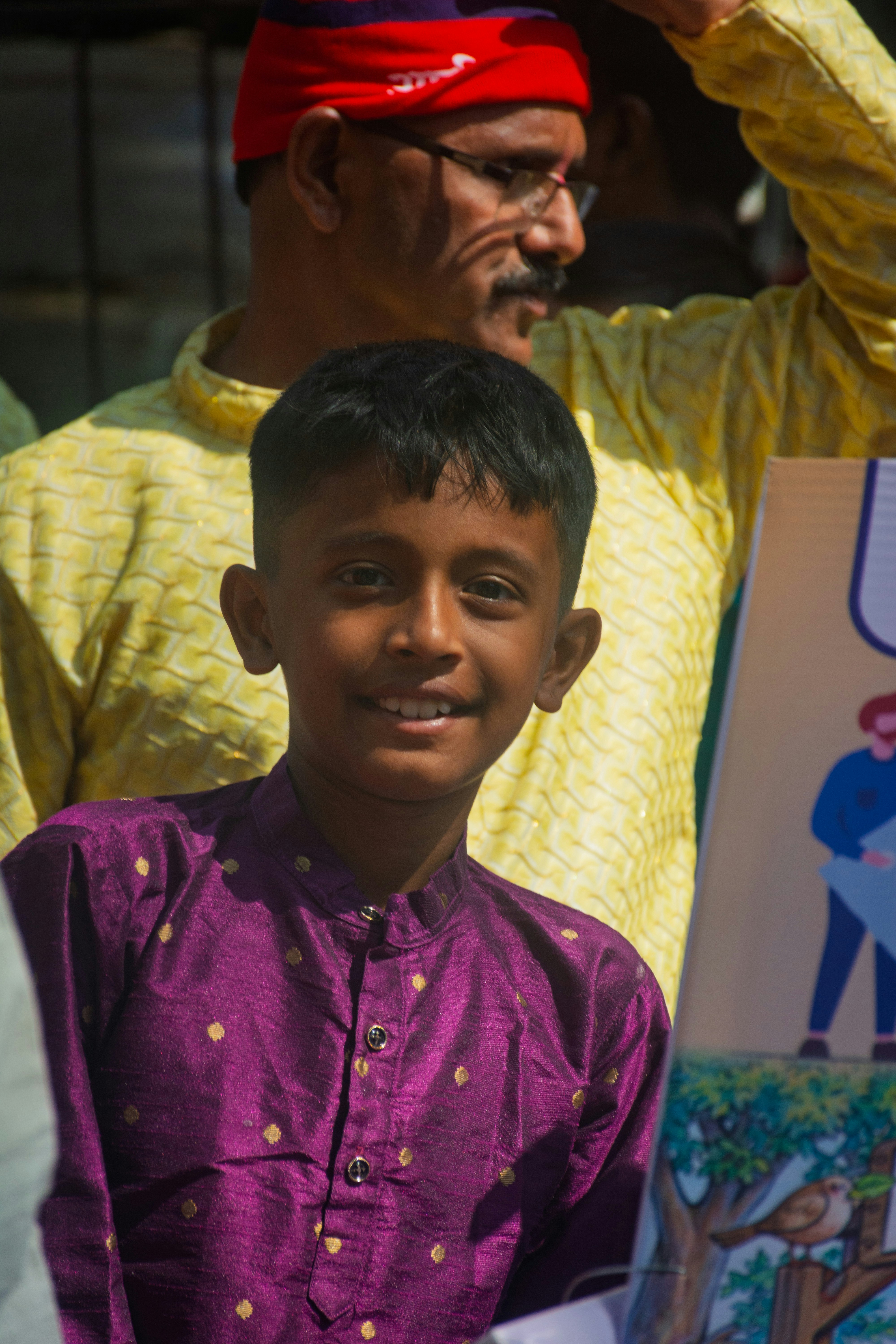 Portrait at a Festival Booth: A Smiling Boy in Rich Purple Amidst Yellow Garb