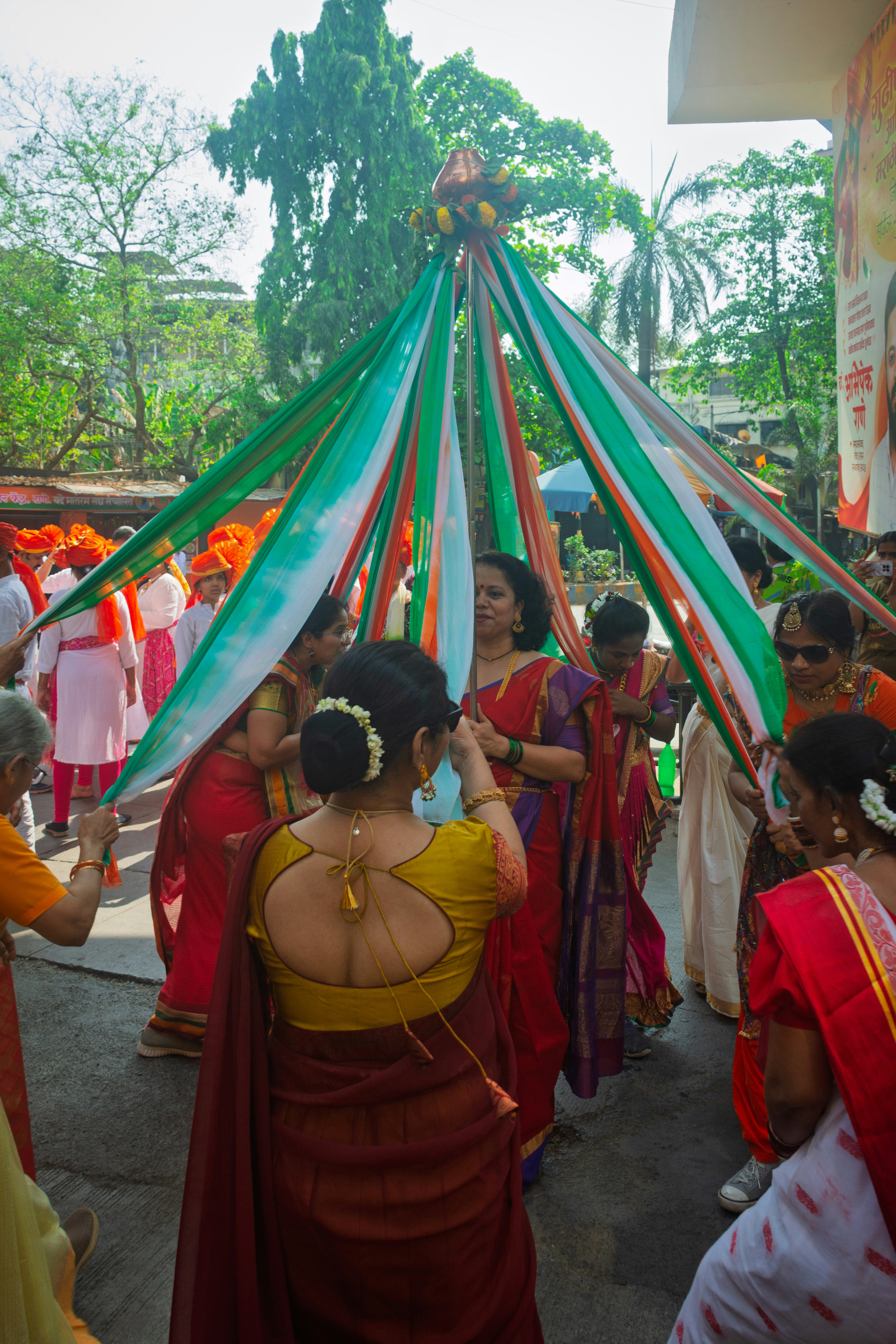 Colorful Shrine Dance: Women in Sarees Share a Festive Moment Under Ribboned Poles
