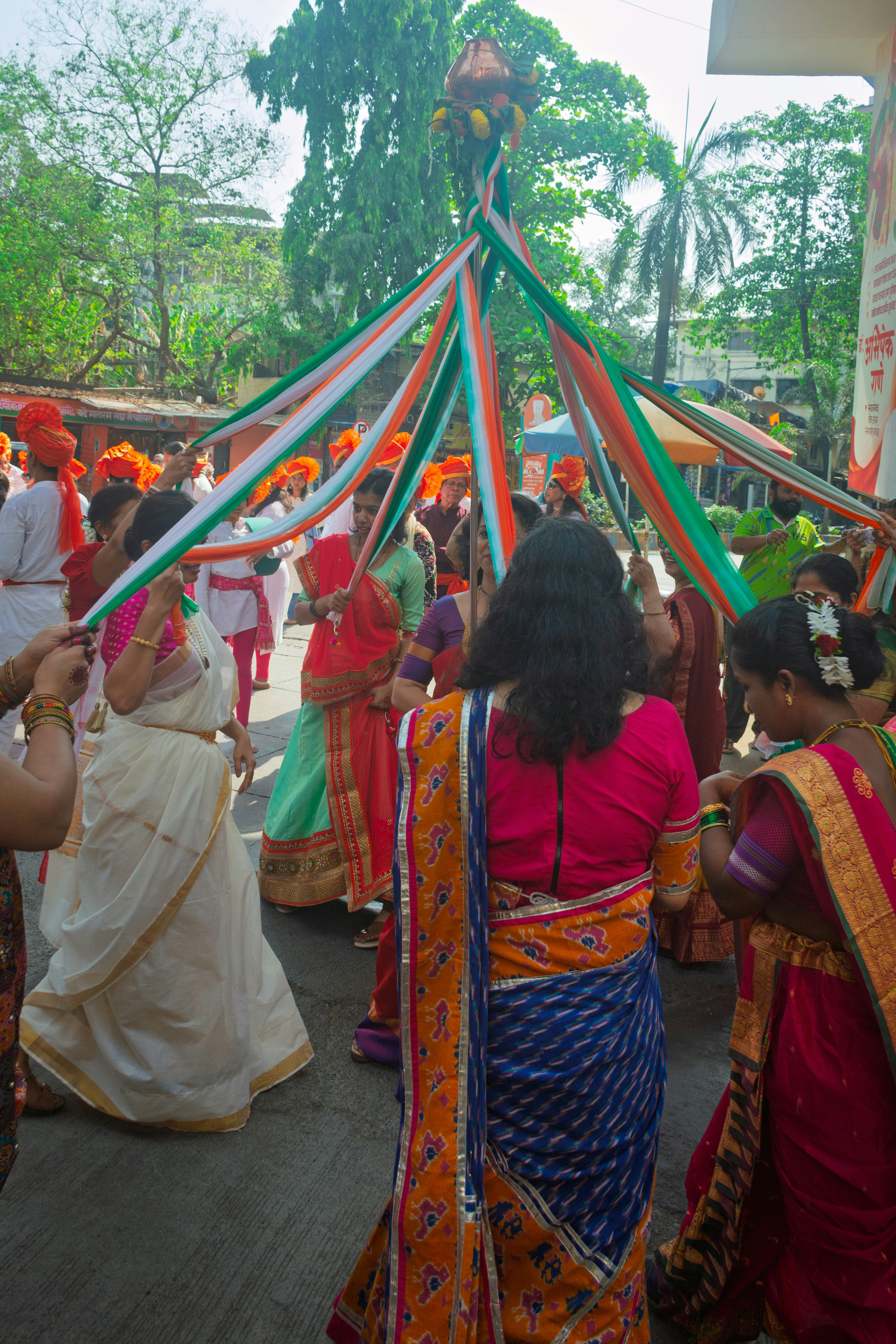 Colorful congregational dance around a striped maypole during a festive procession
