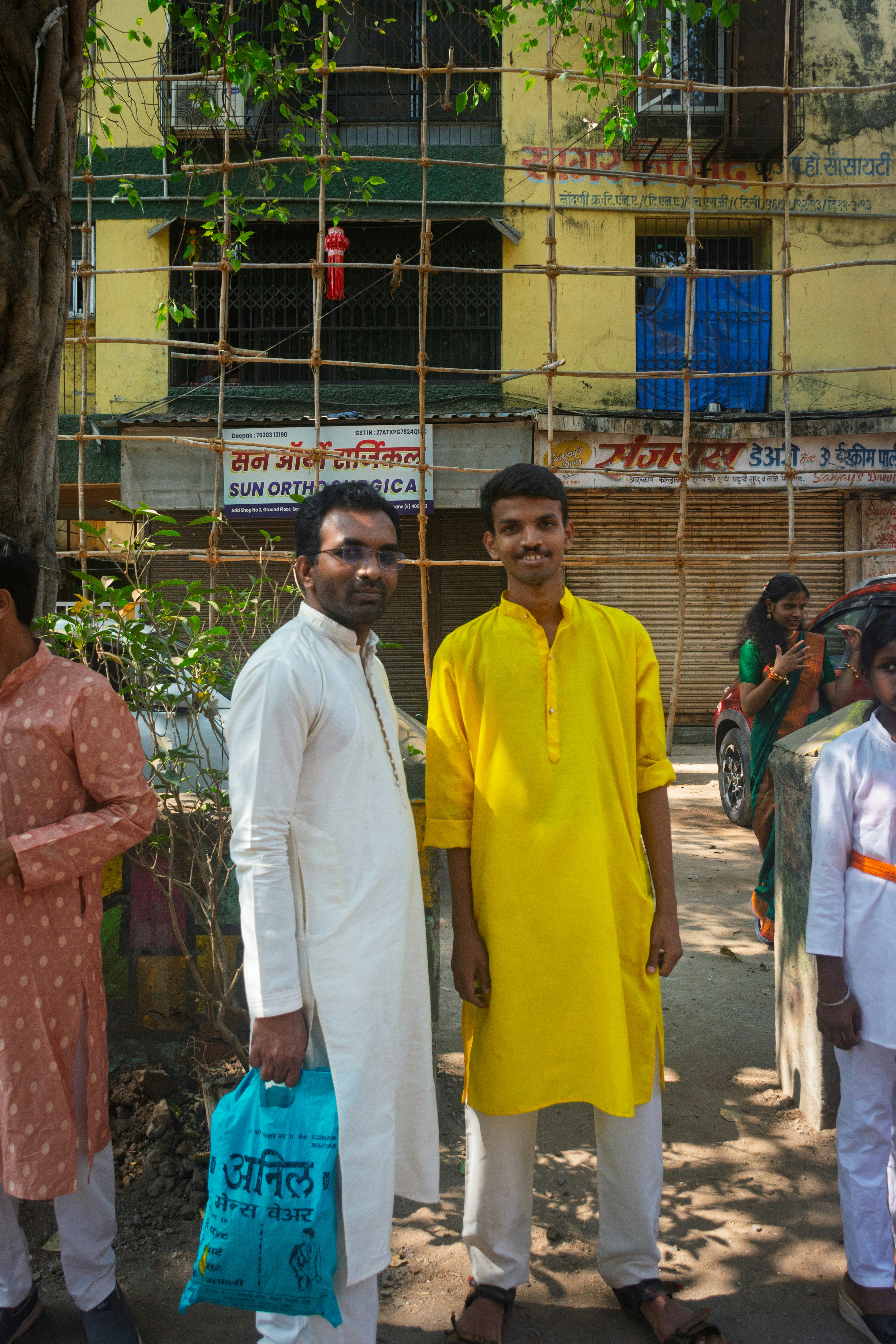 Three Friends in Colorful Traditional Attire Stand Out Under a Shaded Street Scene