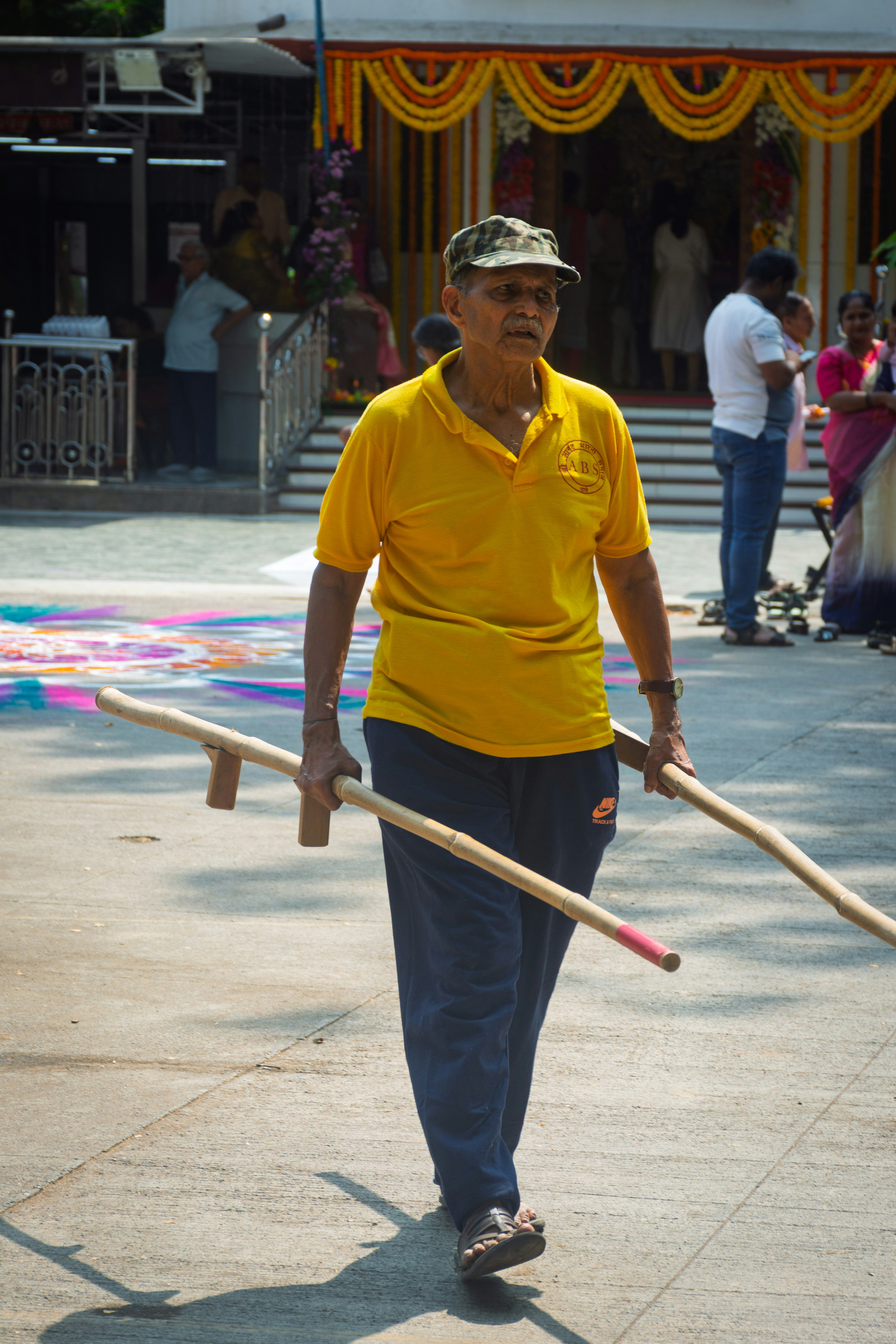 Yellow-shirted street performer with bamboo props in a temple plaza
