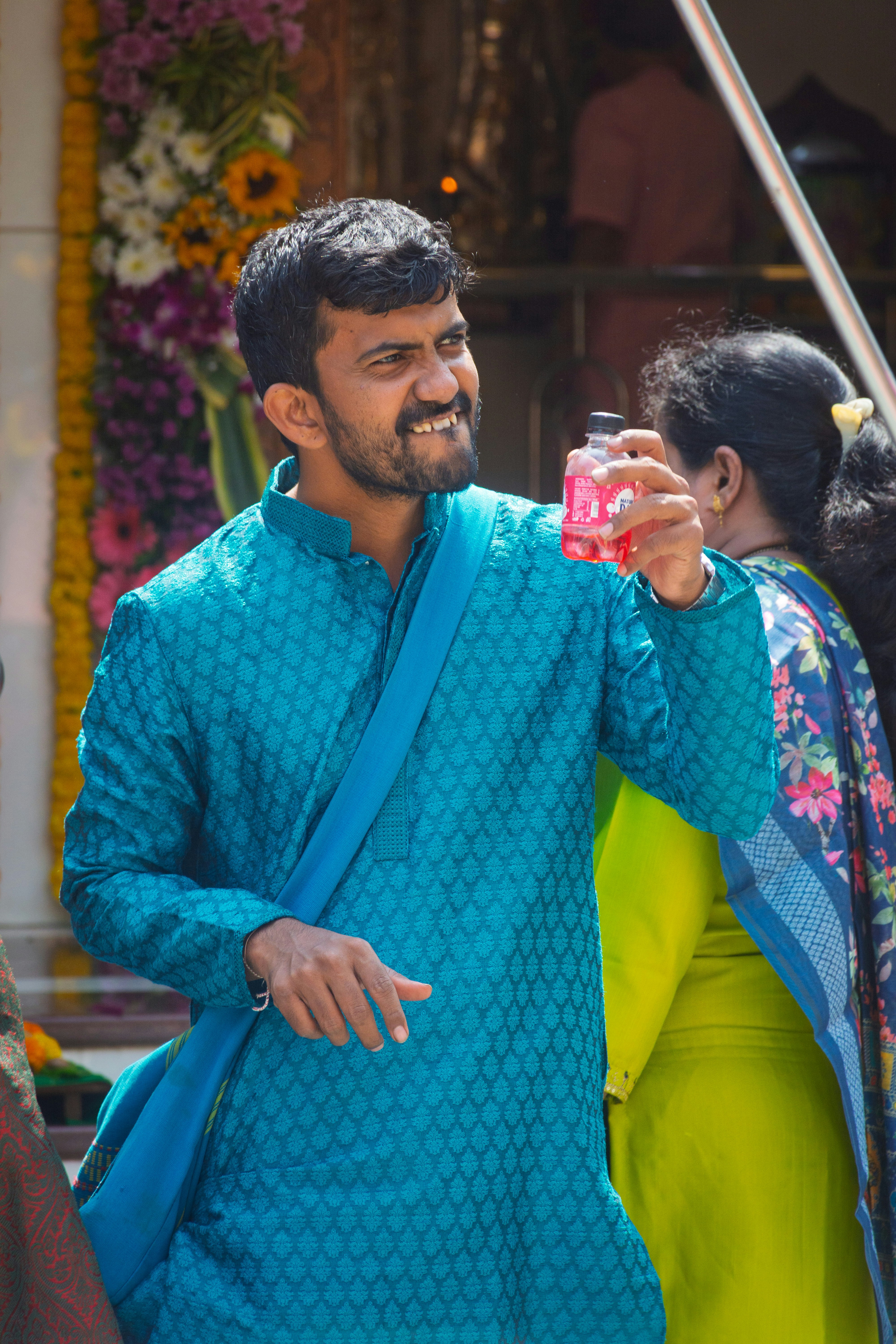 Smiling Moment with a Pink Drink at a Colorful Festival