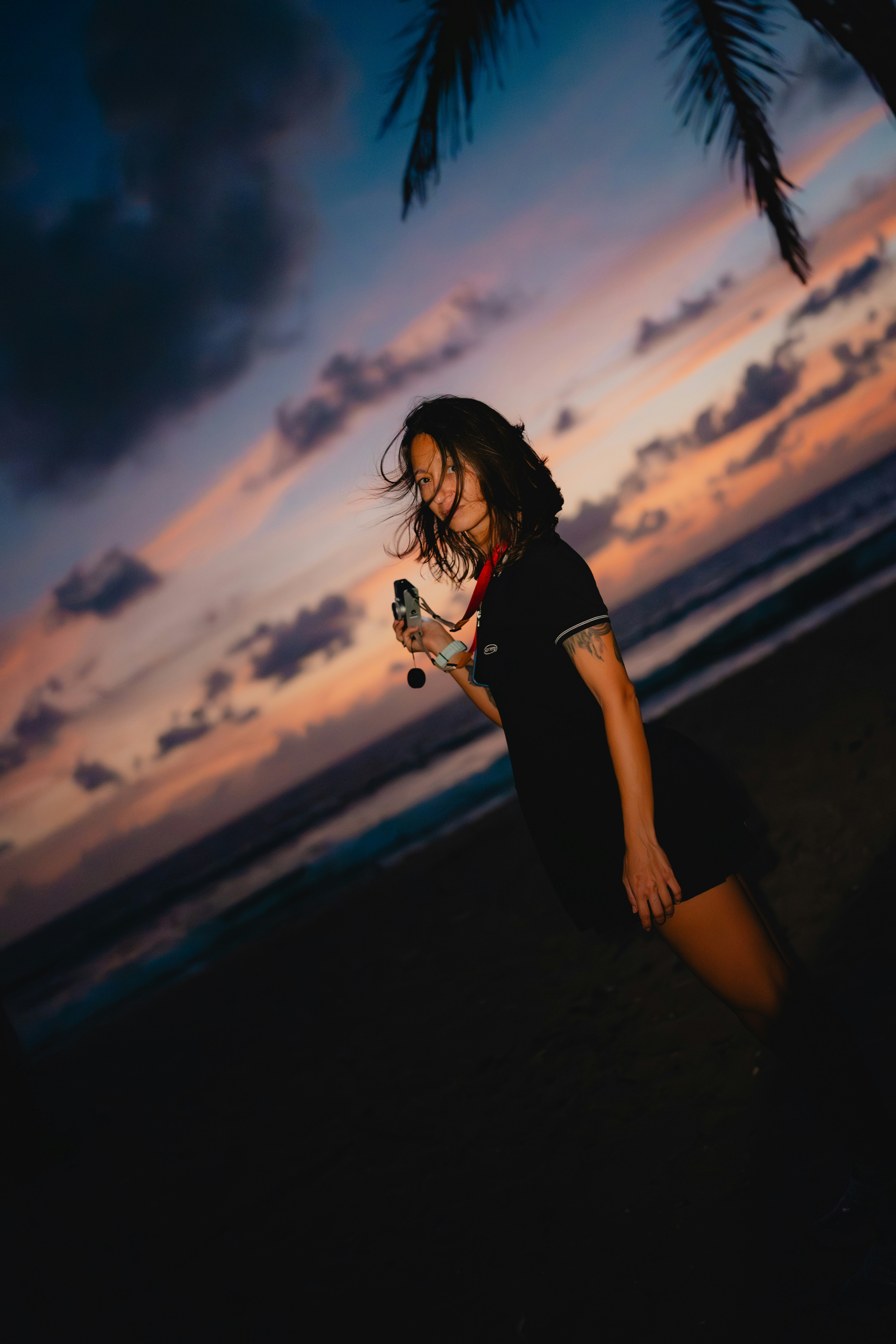 Midnight Beach Moment: Silhouette of a Woman with a Microphone Under Palm Fronds