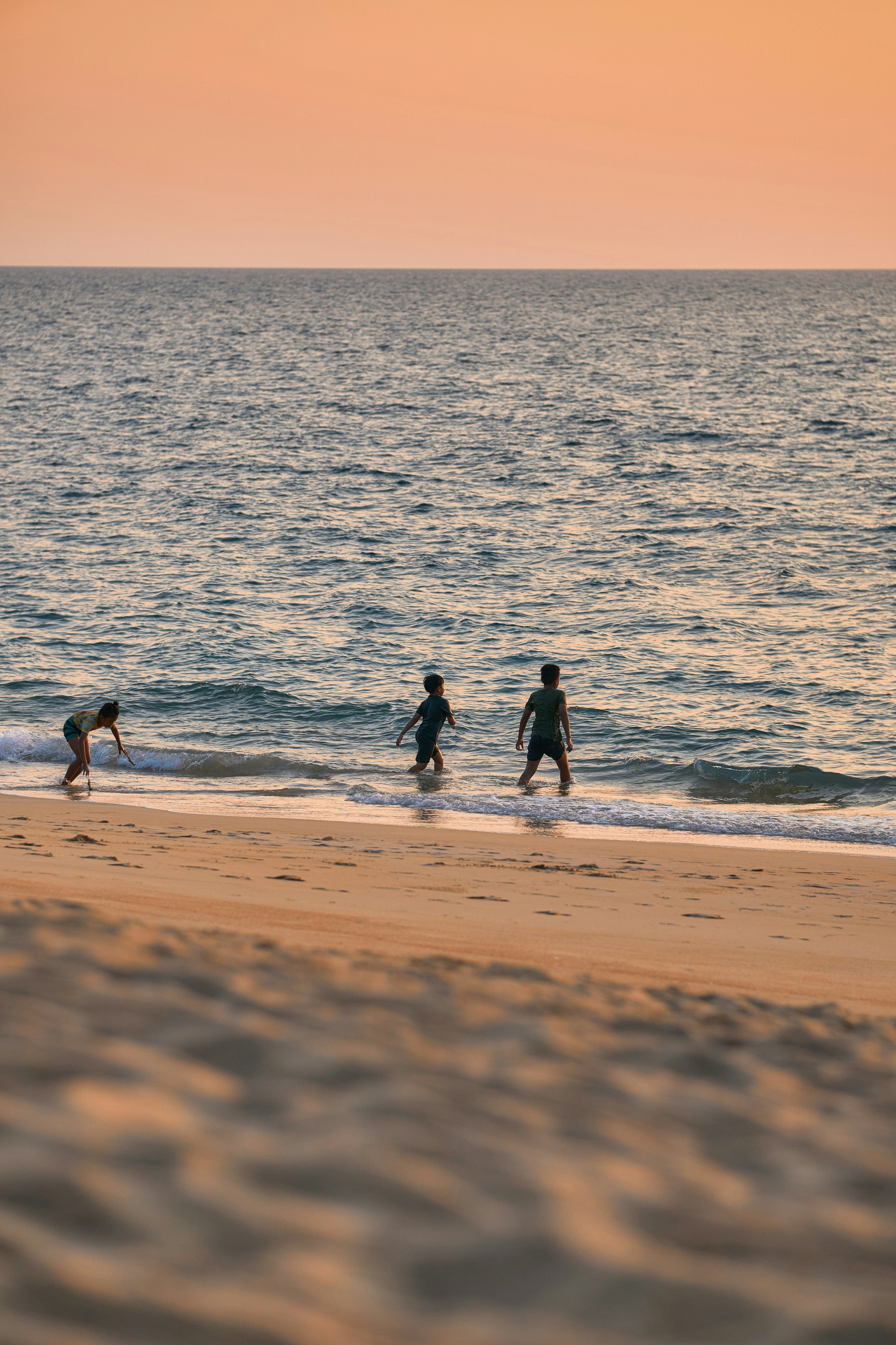 Three silhouettes at the shoreline at sunset
