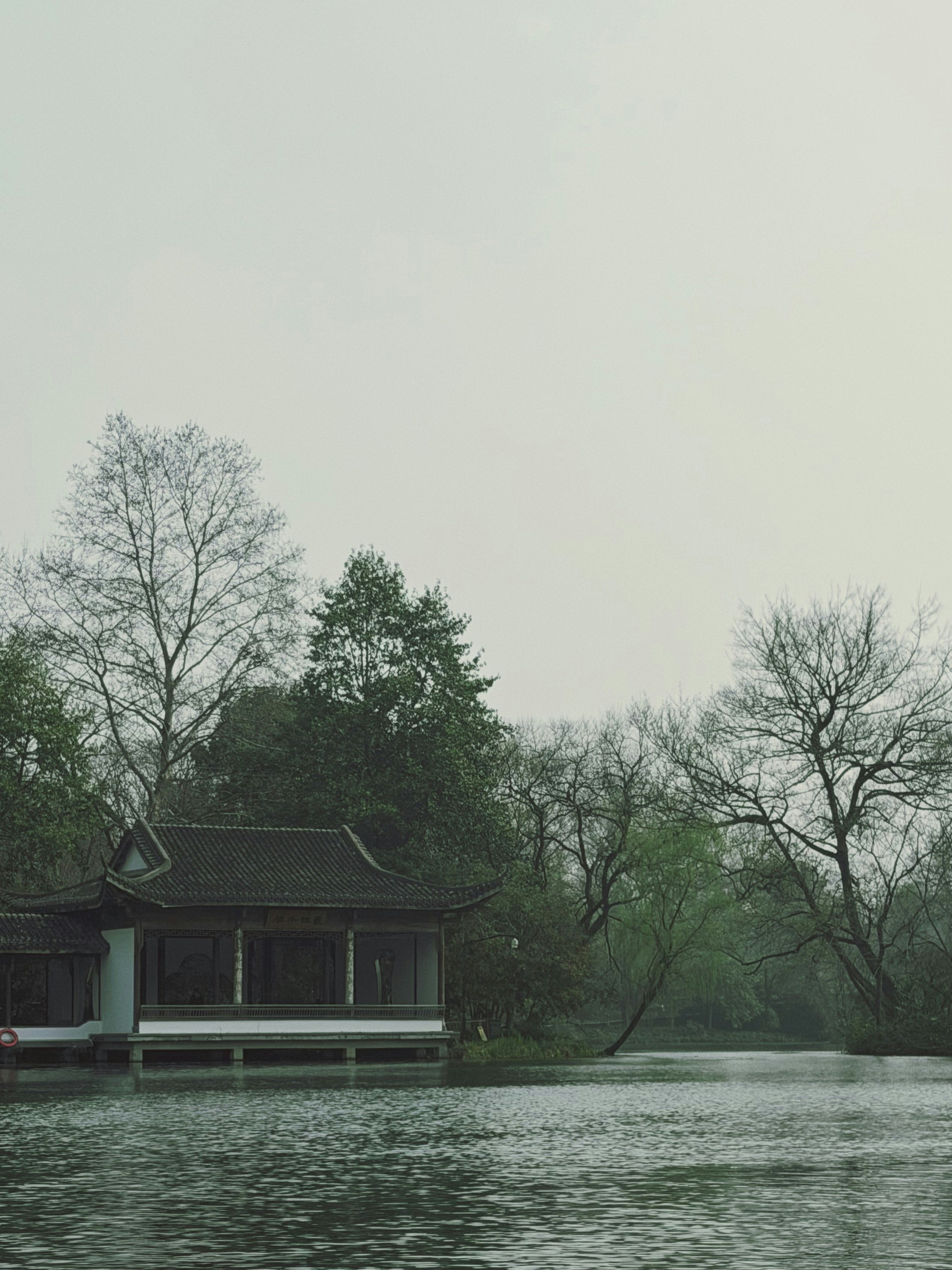  tranquil lakeside pavilion framed by bare trees at dusk 