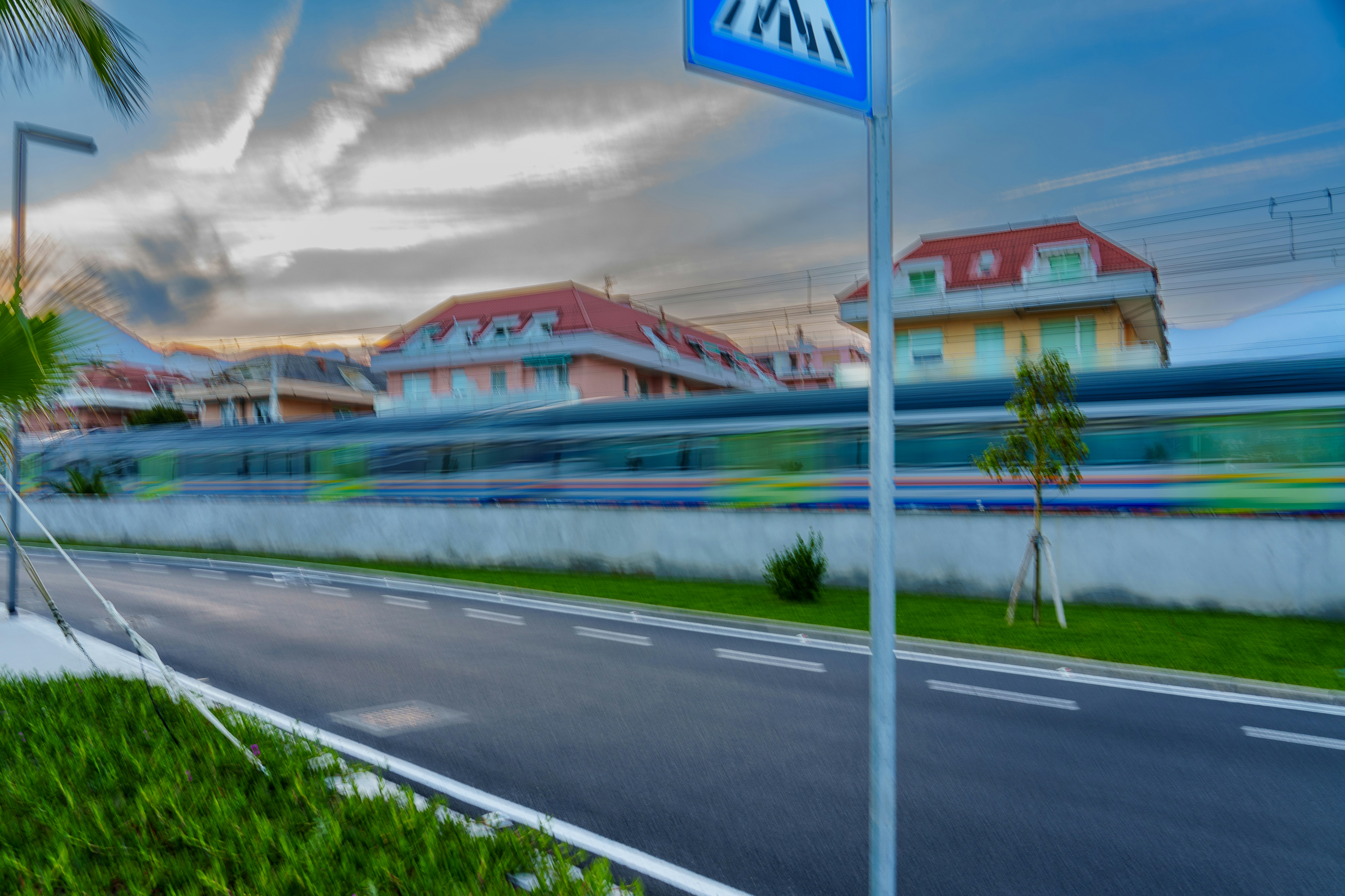 Blurred Train Rush Over a Quiet Green Street