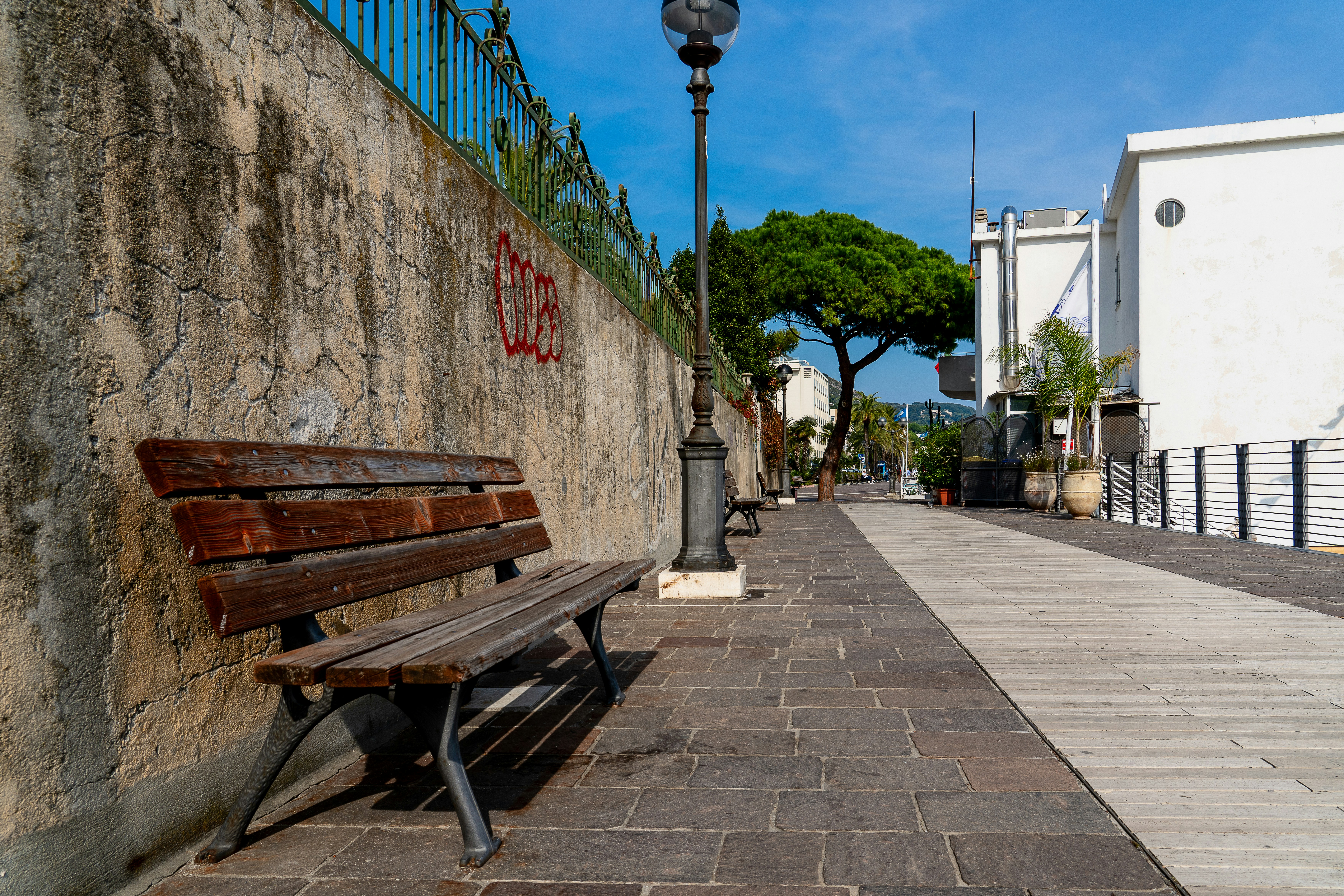 Quiet riverside walkway with a weathered bench under a blue sky