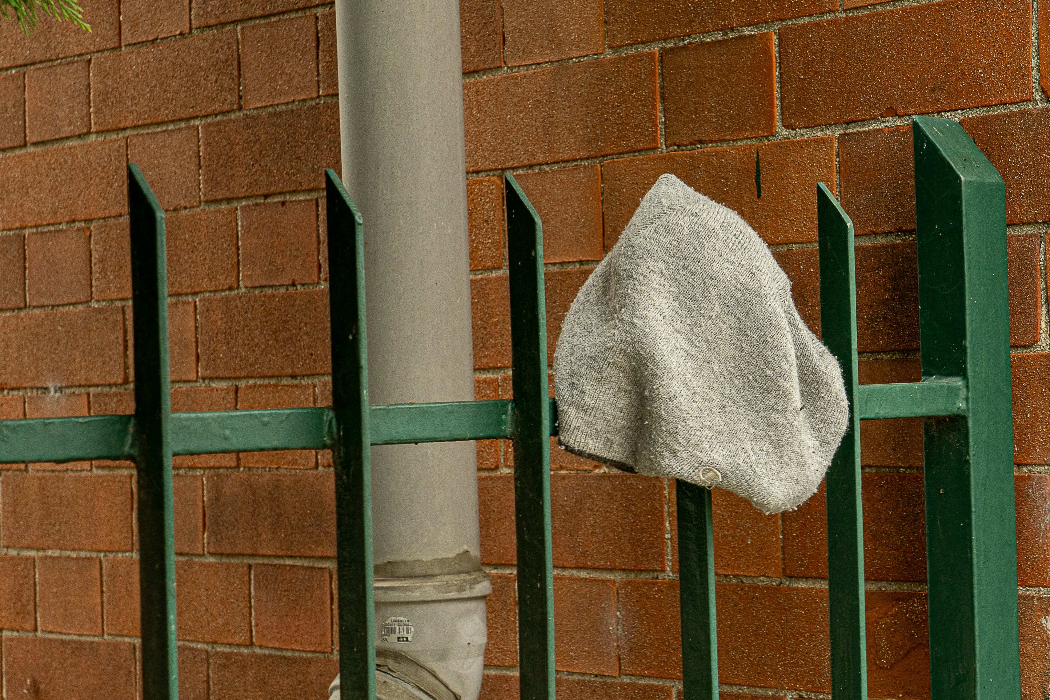 Cloth Adrift on a Green Railing Against Brick