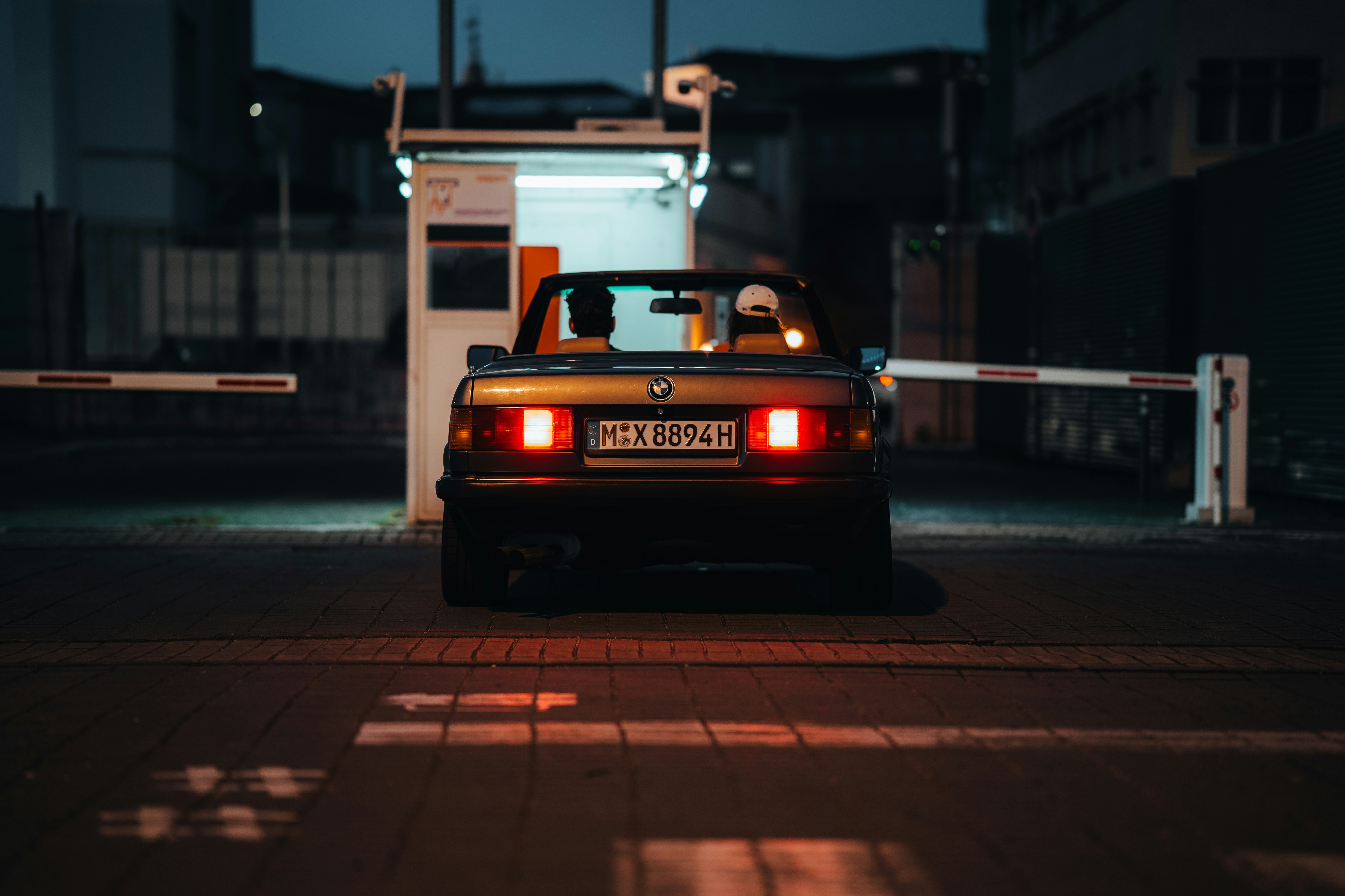 Midnight Car at the Gate: Neon Reflections on a Quiet Barrier