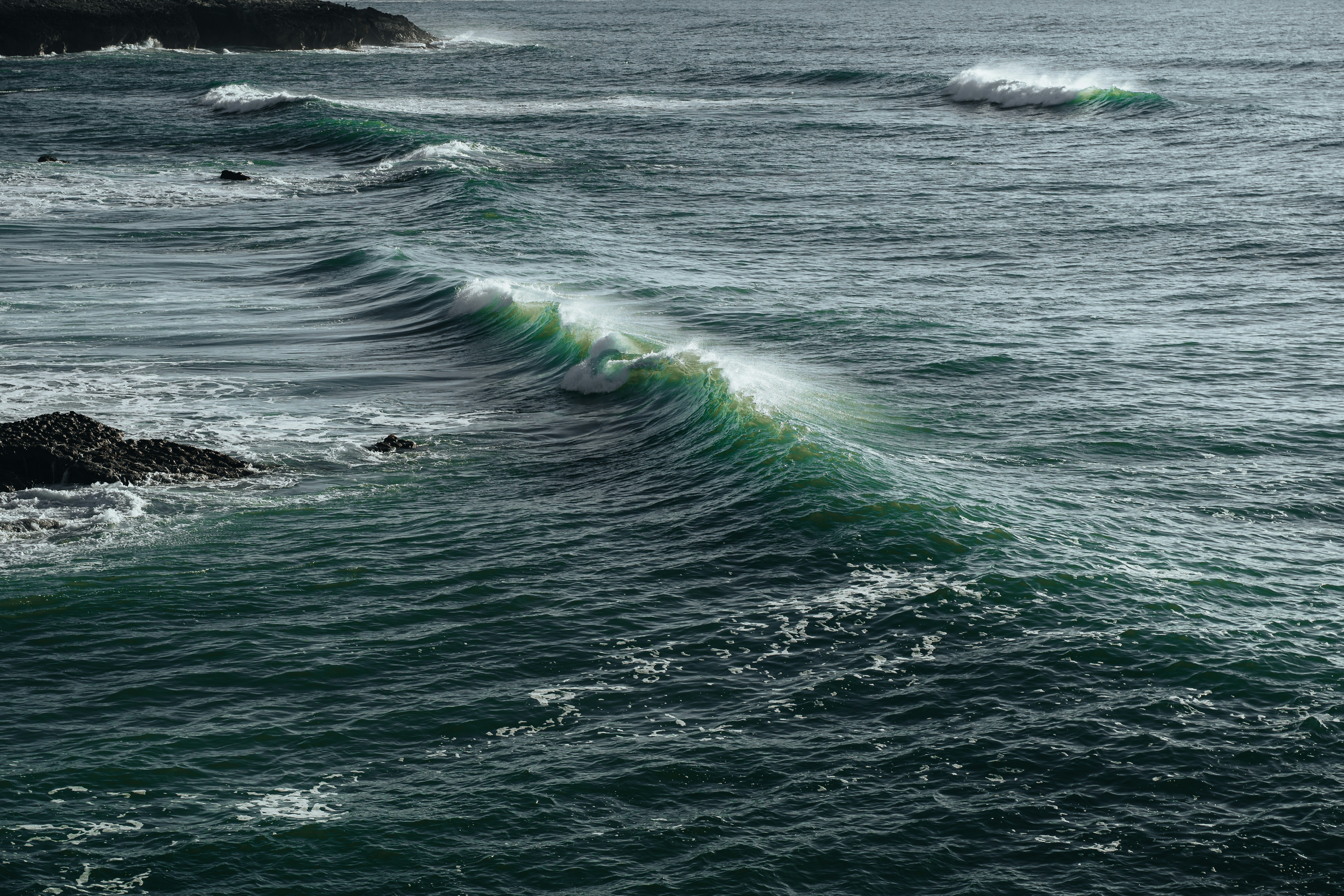 A rolling emerald crest over deep blue seas