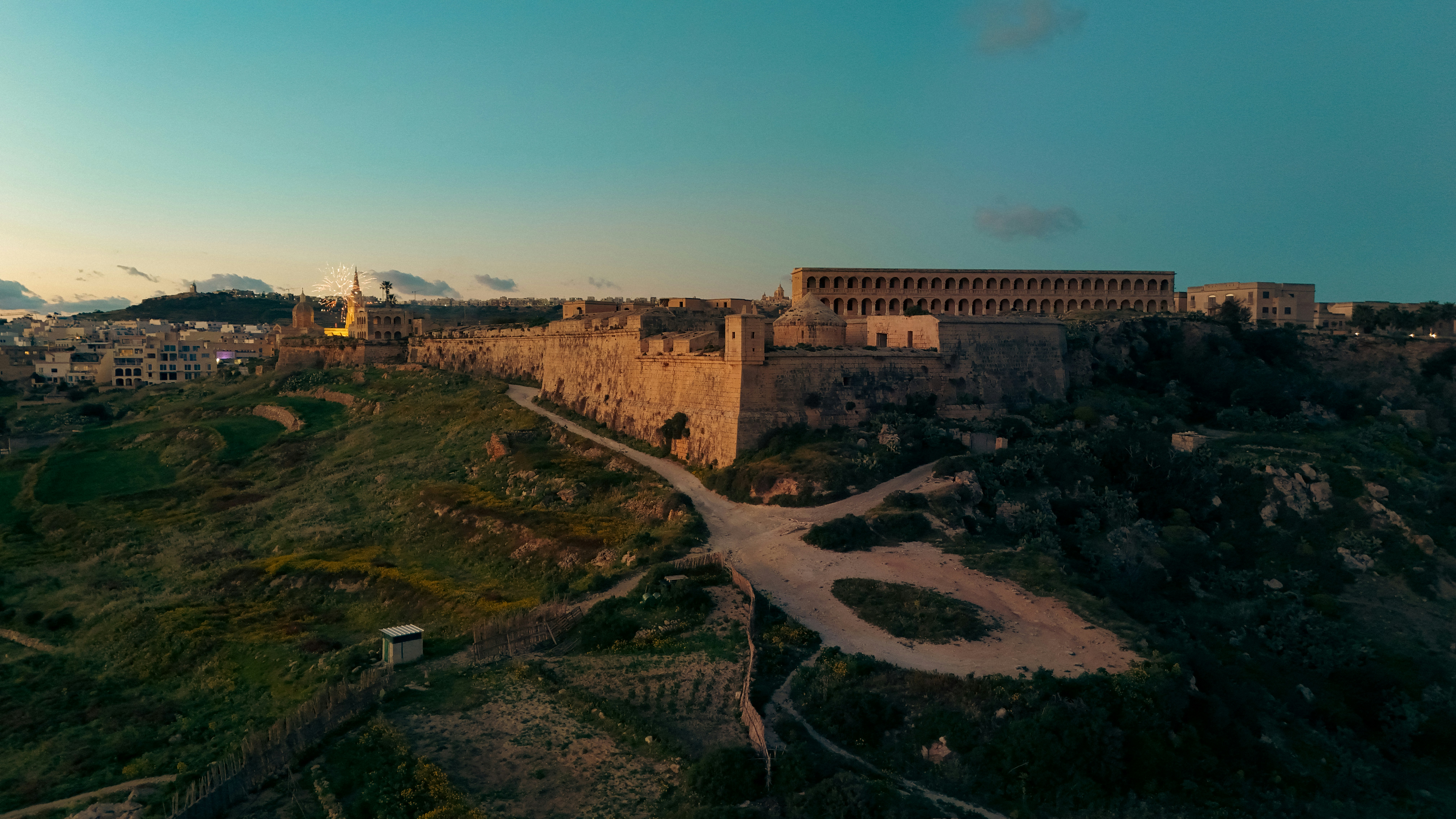 Fortress under the evening sky: ancient walls and rising hilltop lights