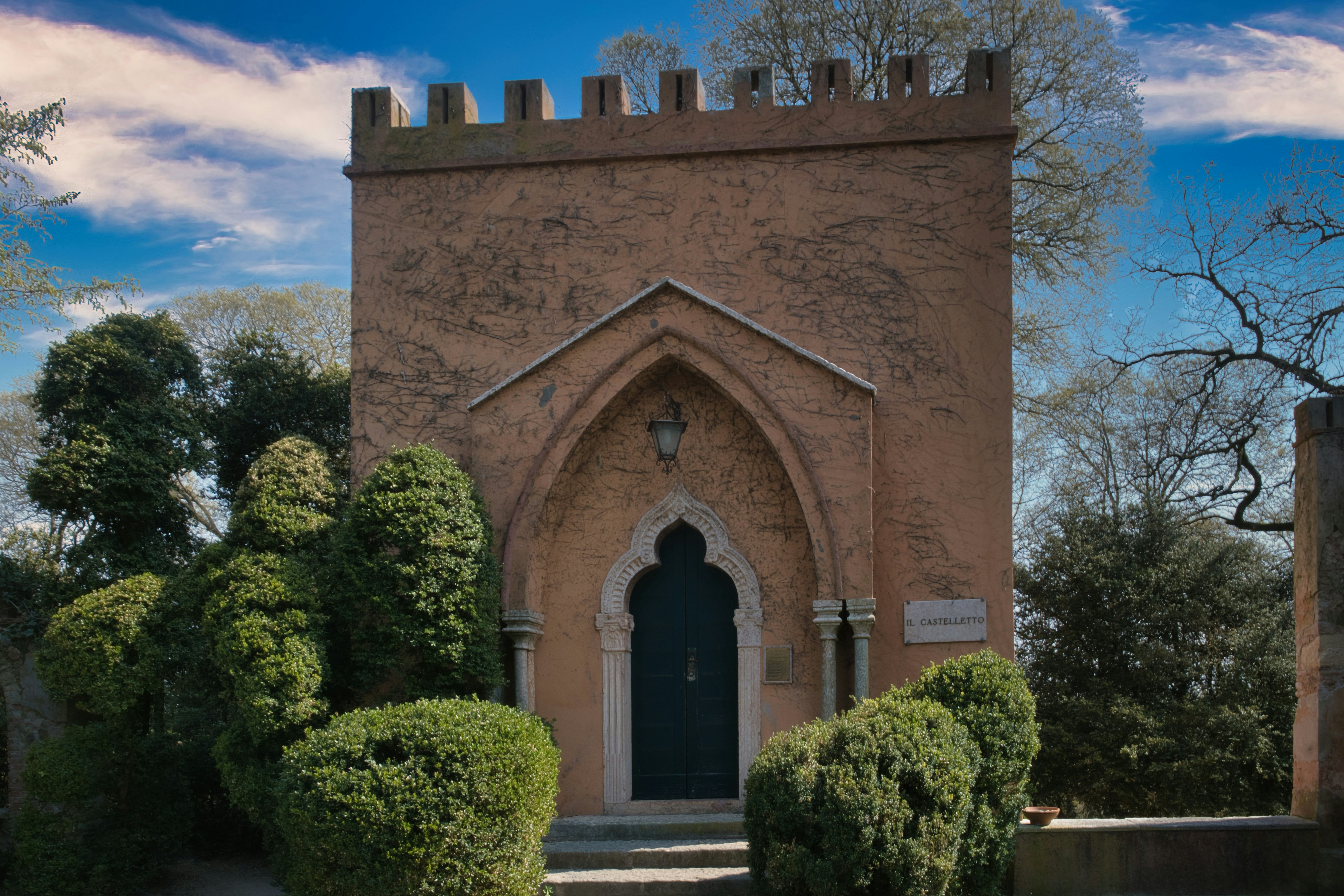 Gothic Archway on a Brick Facade Surrounded by Pruned Shrubs