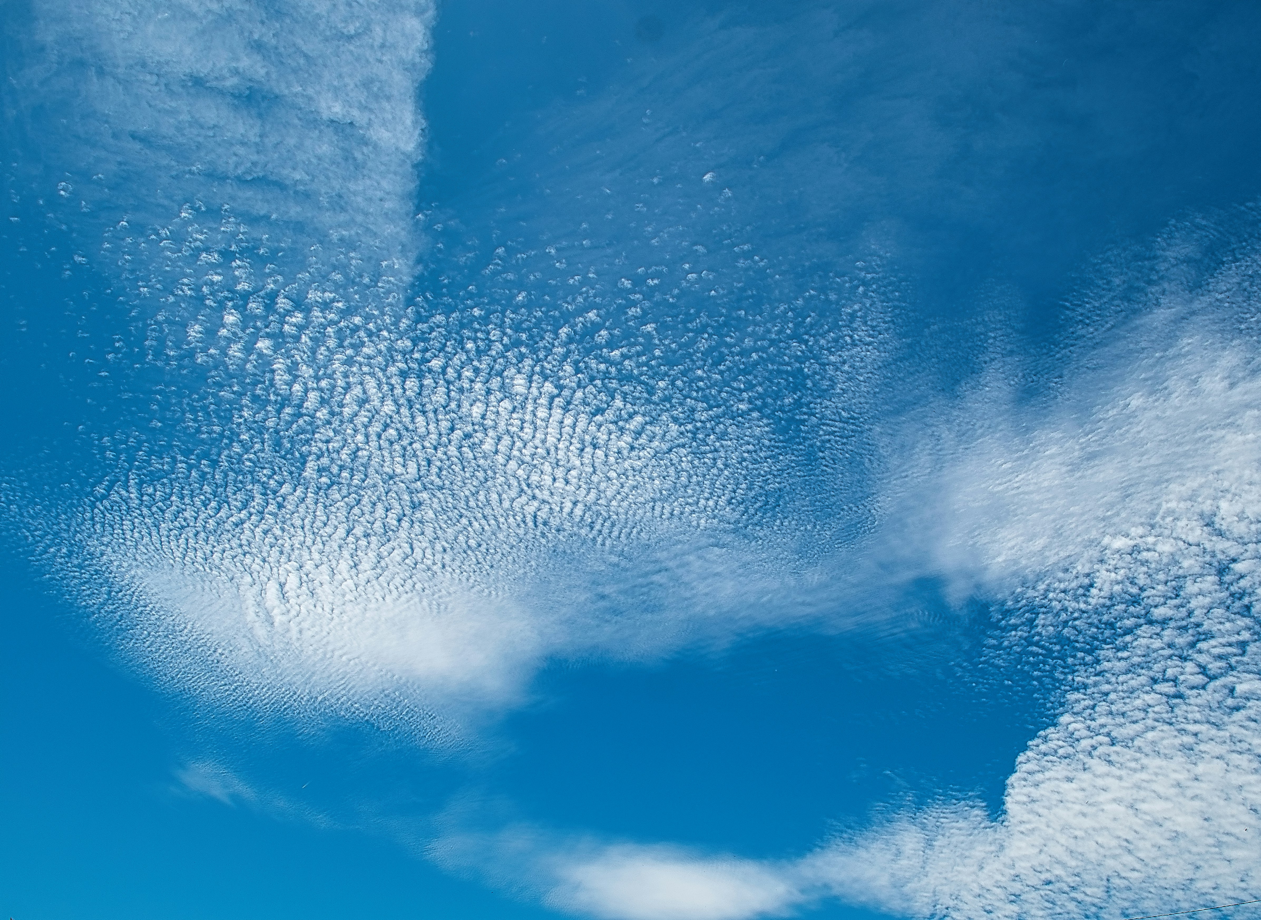 Cerulean Skies: A Patchwork of Clouds Across the Blue Expanse