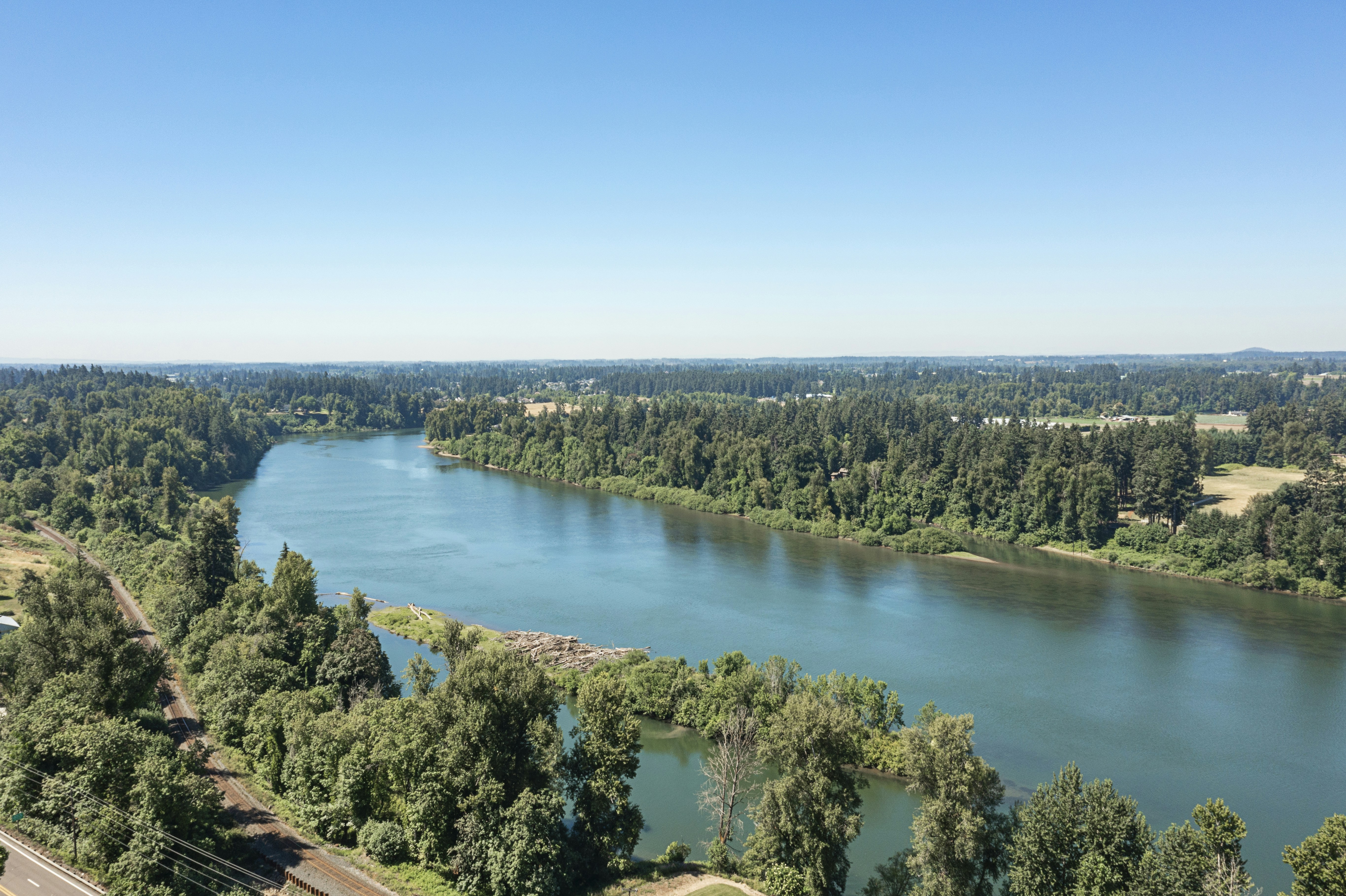River bend panorama: teal waters framed by lush banks under a clear sky