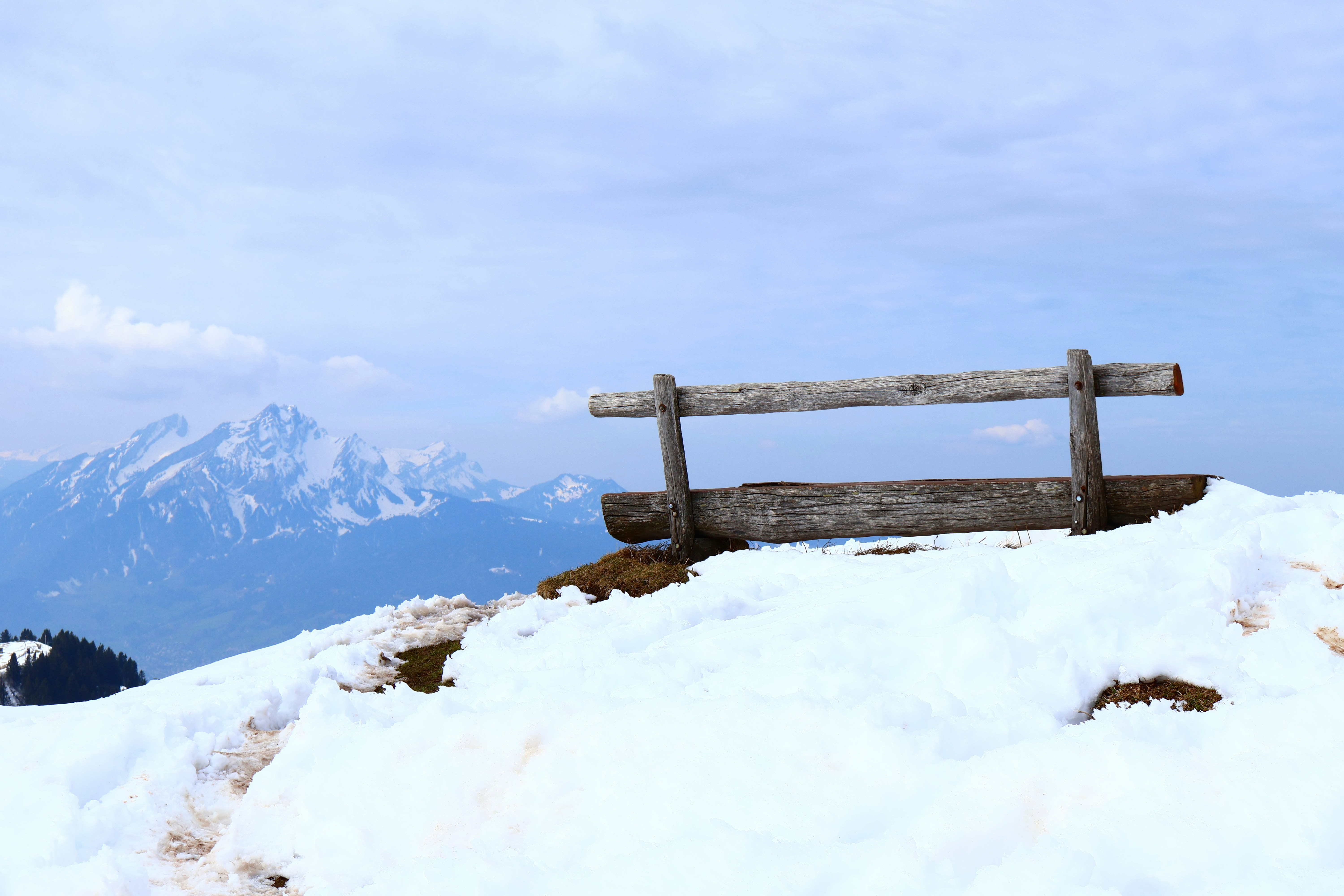 Snowy overlook with weathered railing against alpine vista