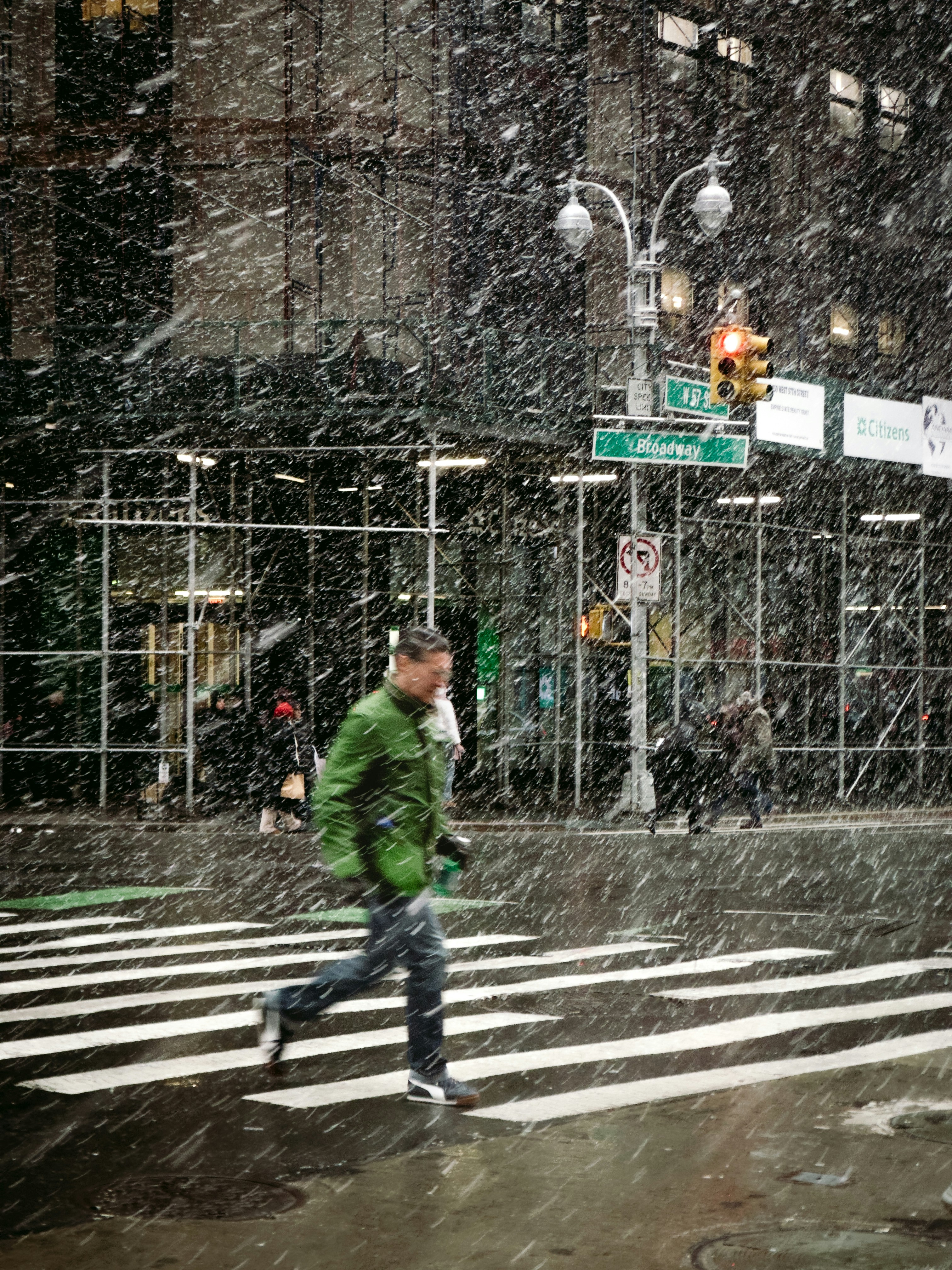 Snowy City Crossing: A Green-Jacketed Pedestrian Braving the Storm