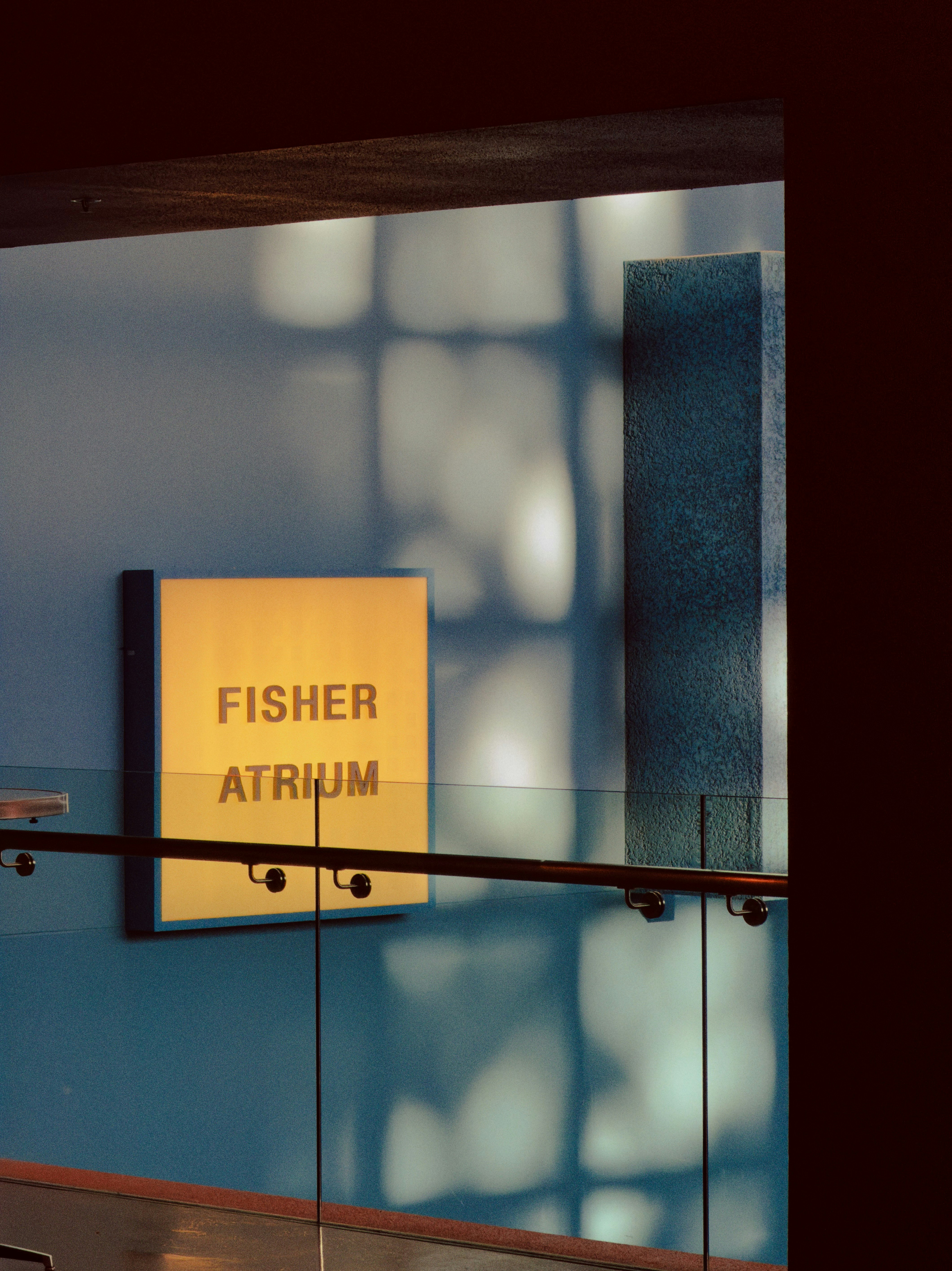 Glow of a Sign: Fisher Atrium Through Glass and Shadow
